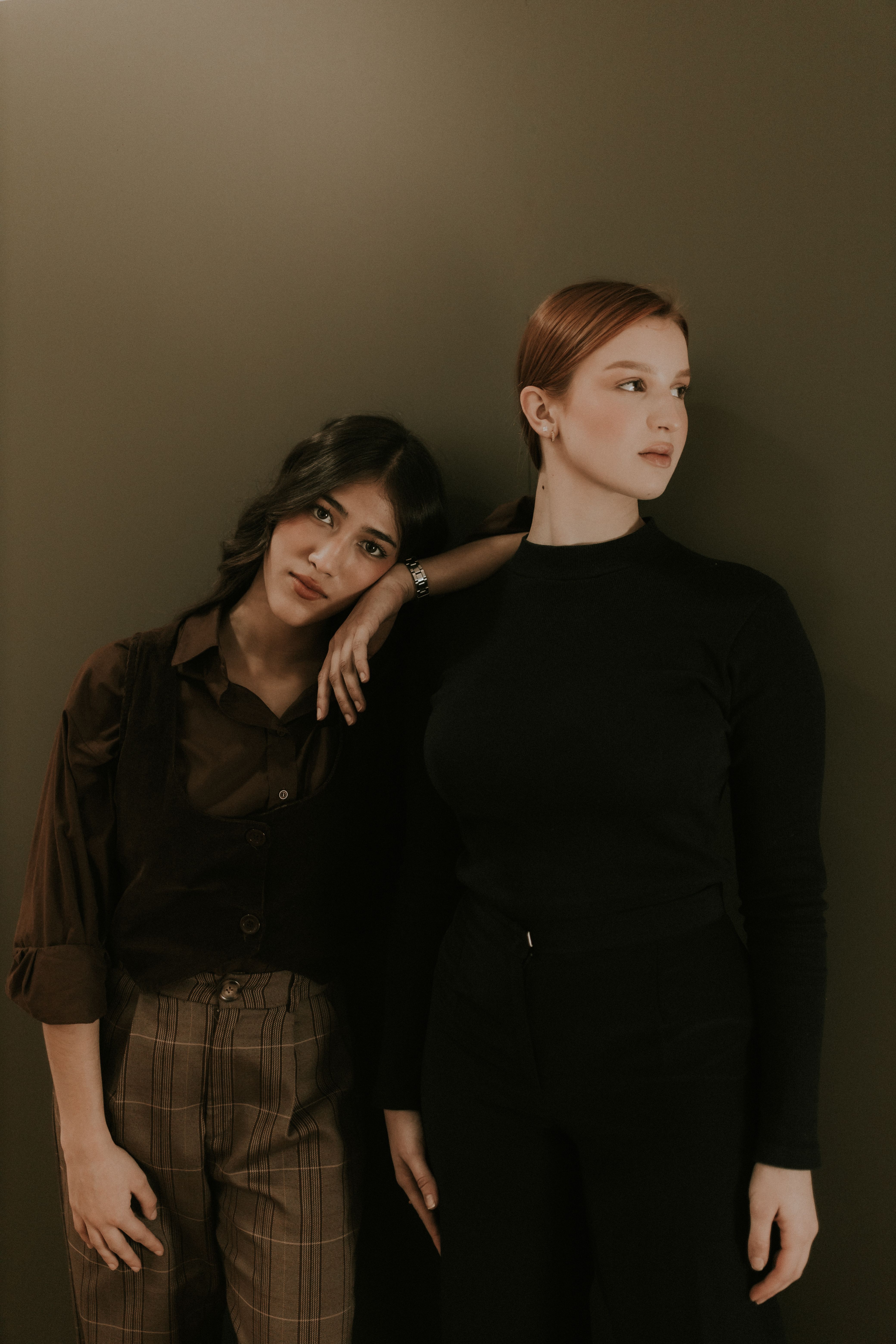 Two women standing next to each other in front of a wall · Free Stock Photo
