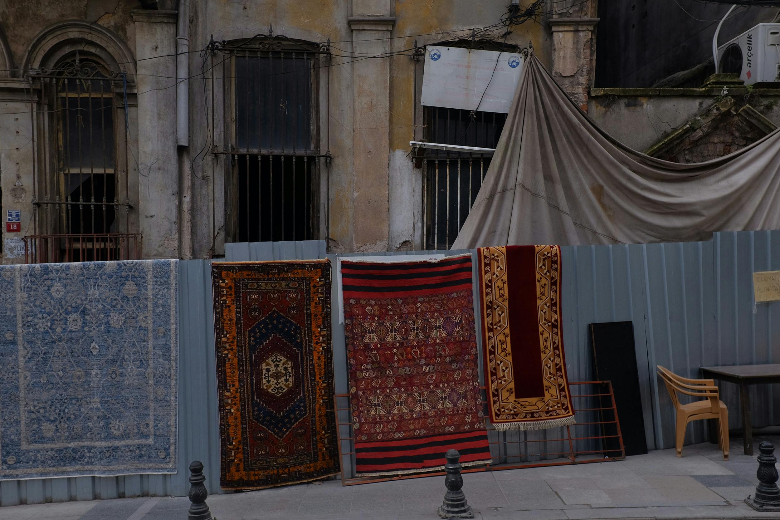 A row of rugs on a sidewalk in front of a building · Free Stock Photo