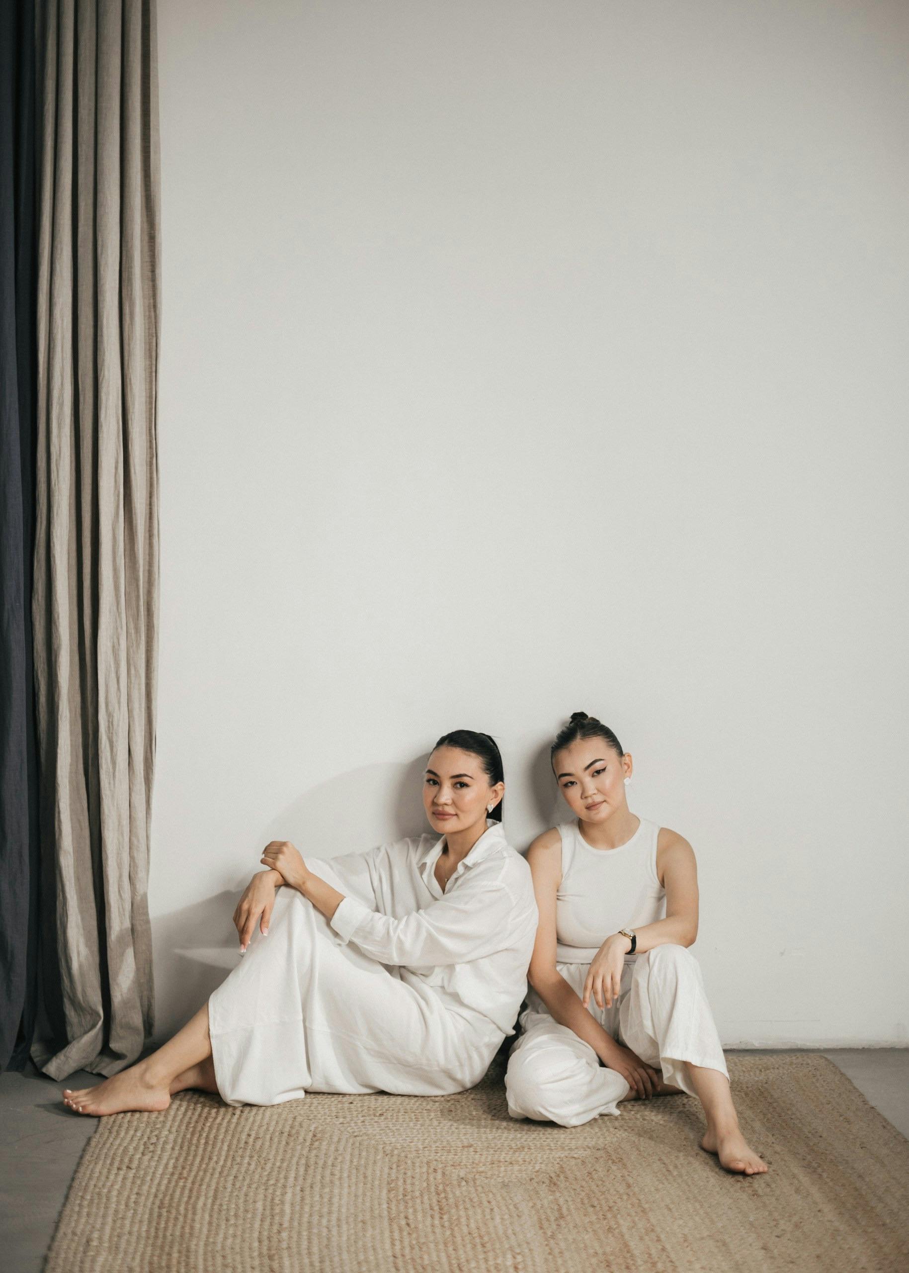 Women in White Clothing Posing together Sitting on Rug · Free Stock Photo