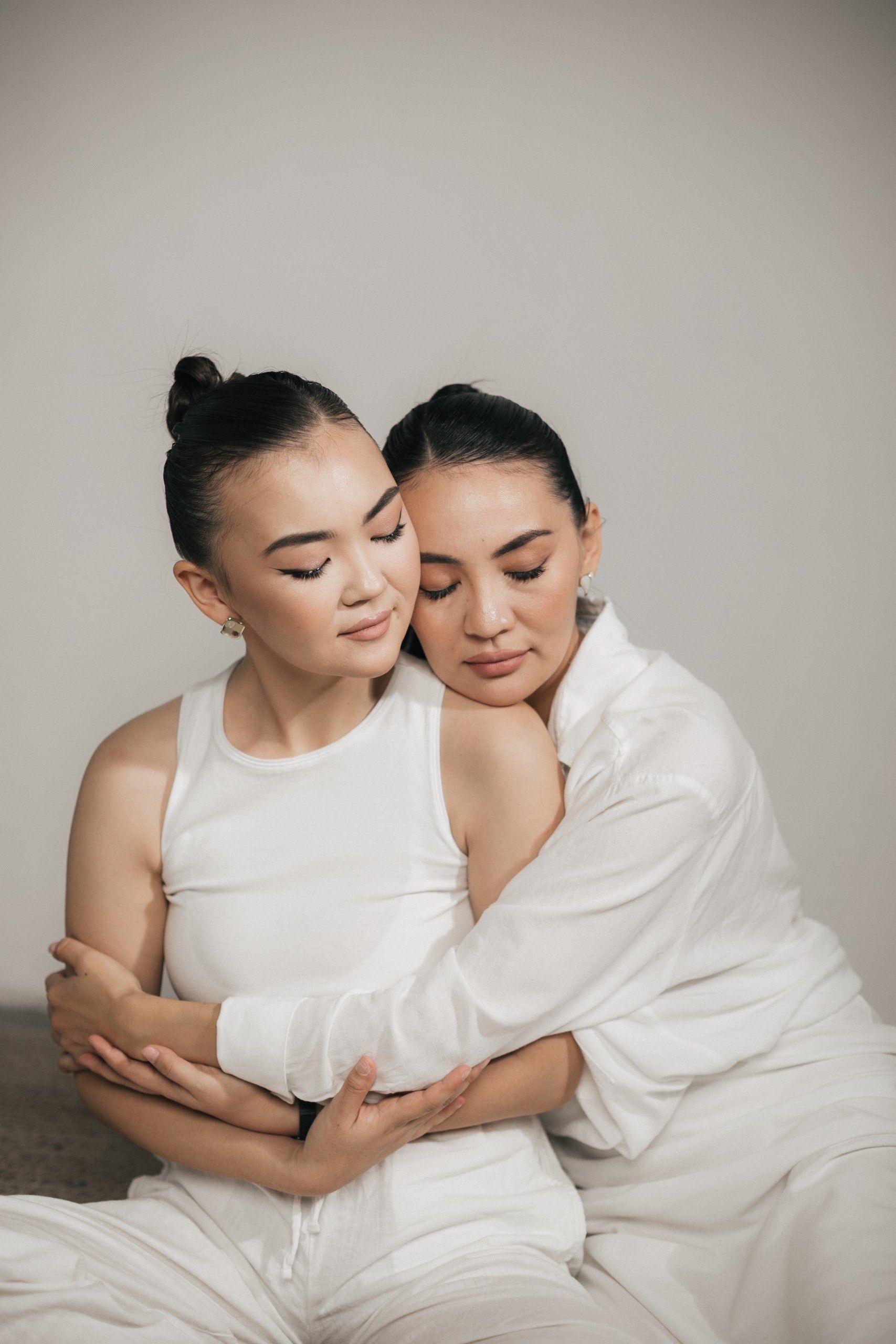 Young Women Sitting Hugging Wearing White Clothing · Free Stock Photo