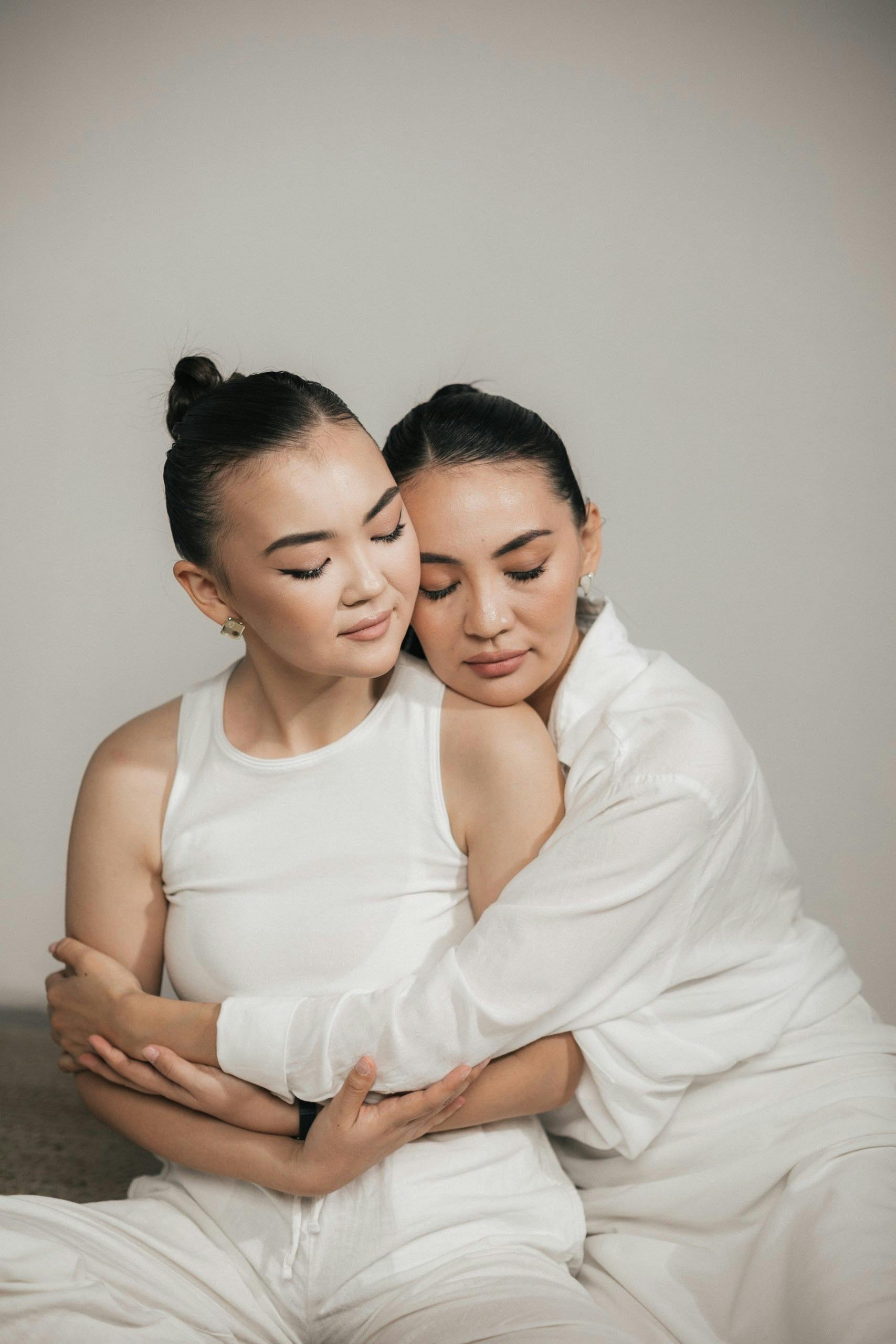 Young Women Sitting Hugging Wearing White Clothing · Free Stock Photo