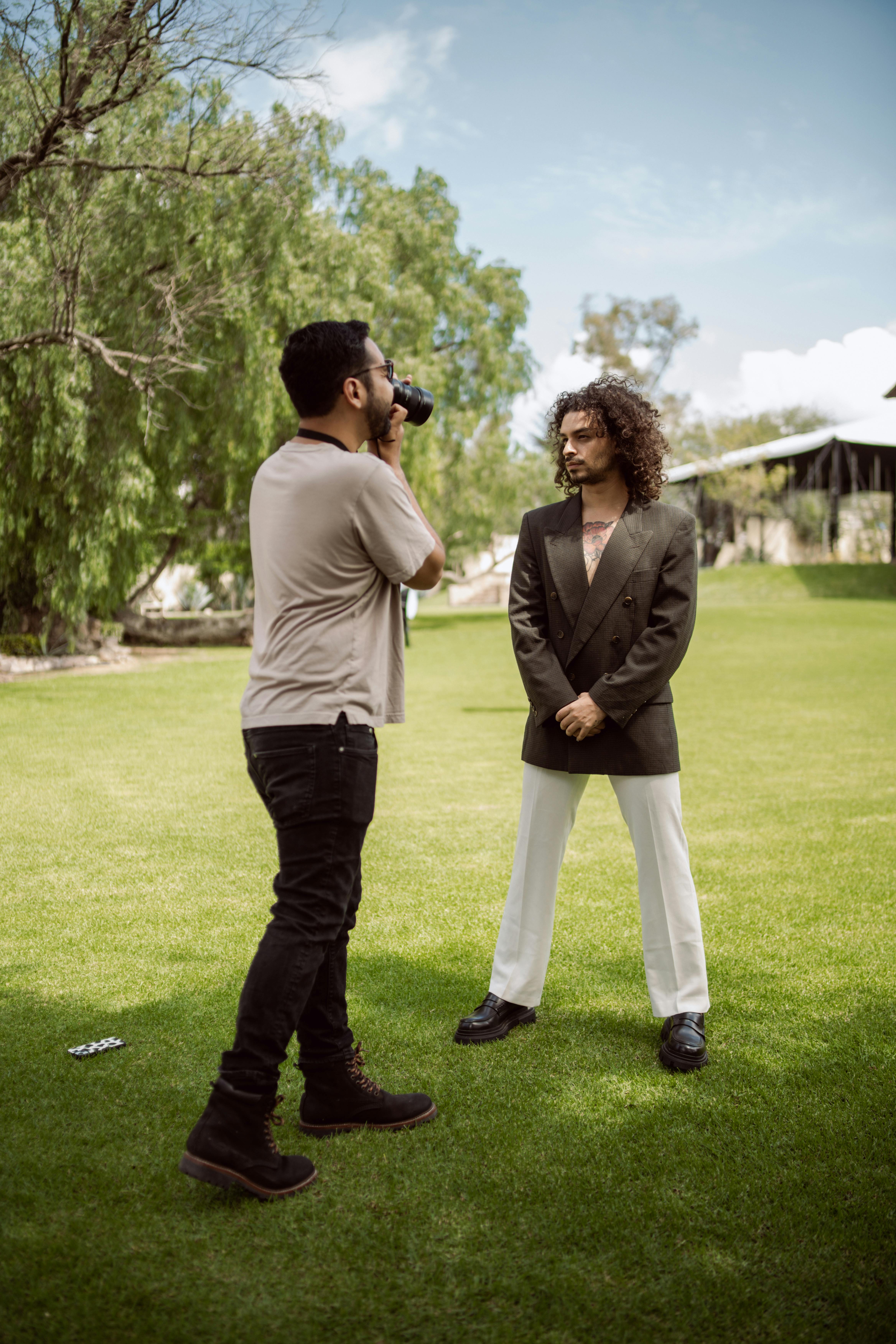 Two men standing in the grass taking pictures · Free Stock Photo