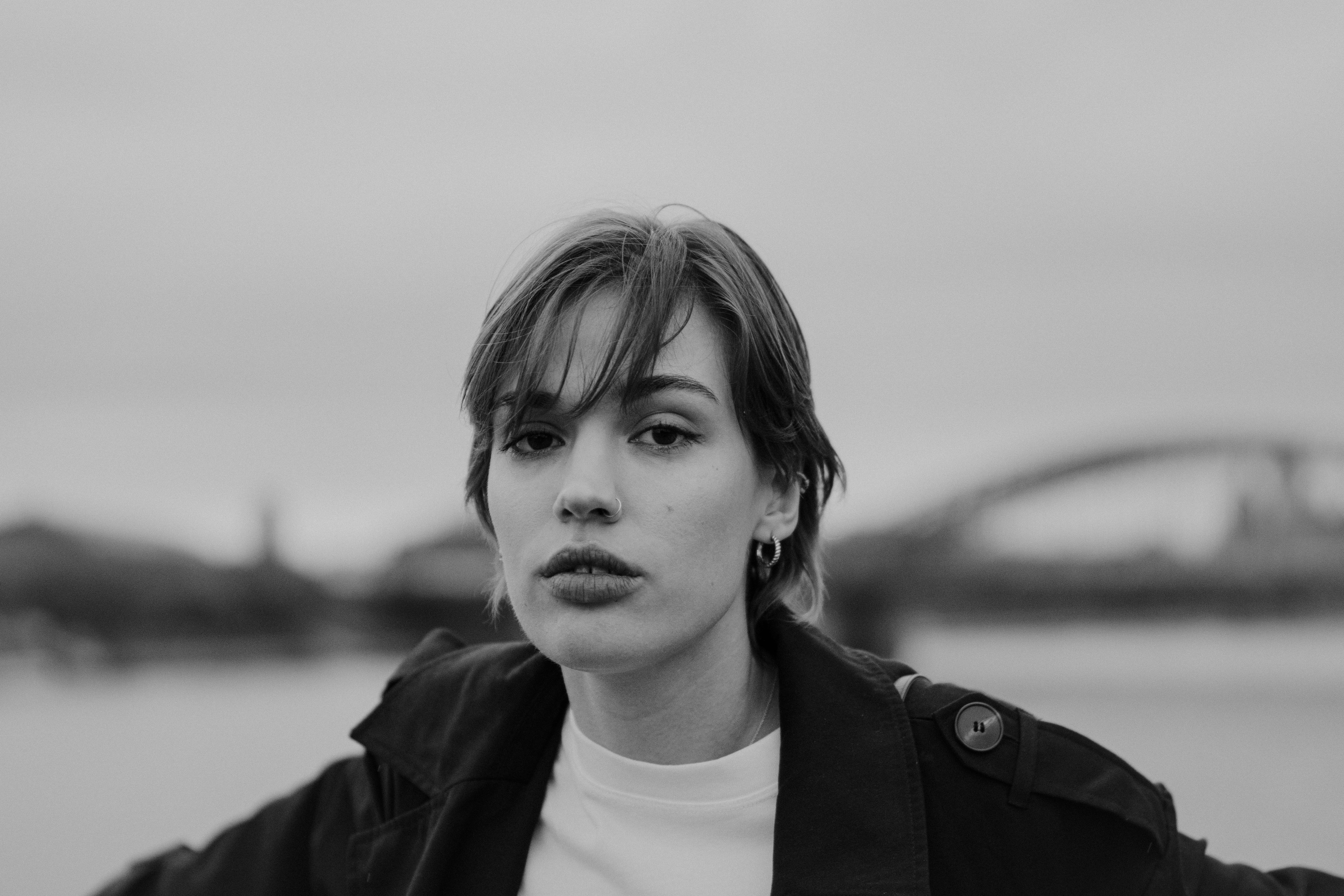 A woman in black and white standing in front of a bridge · Free Stock Photo
