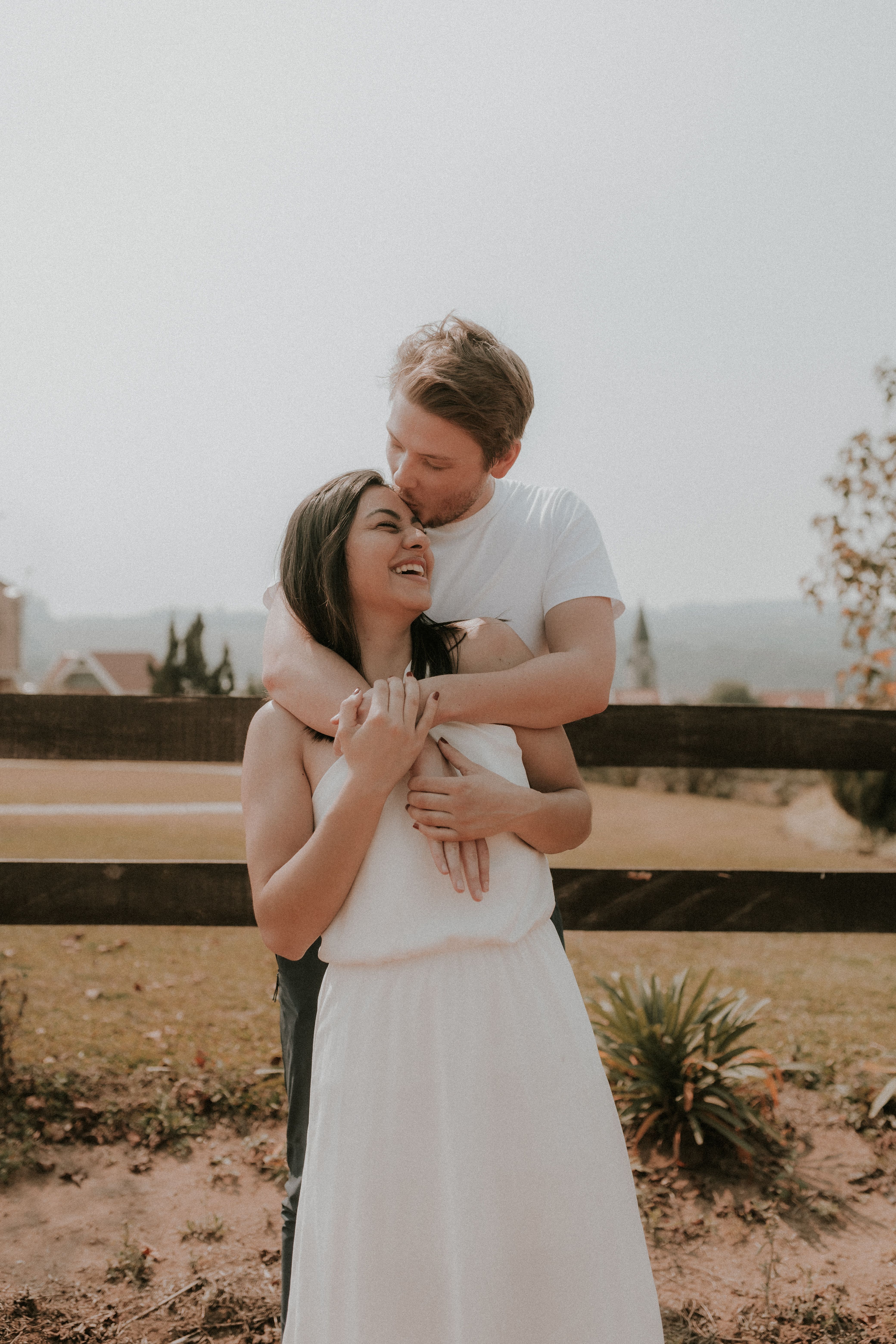 A couple hugging in front of a fence · Free Stock Photo