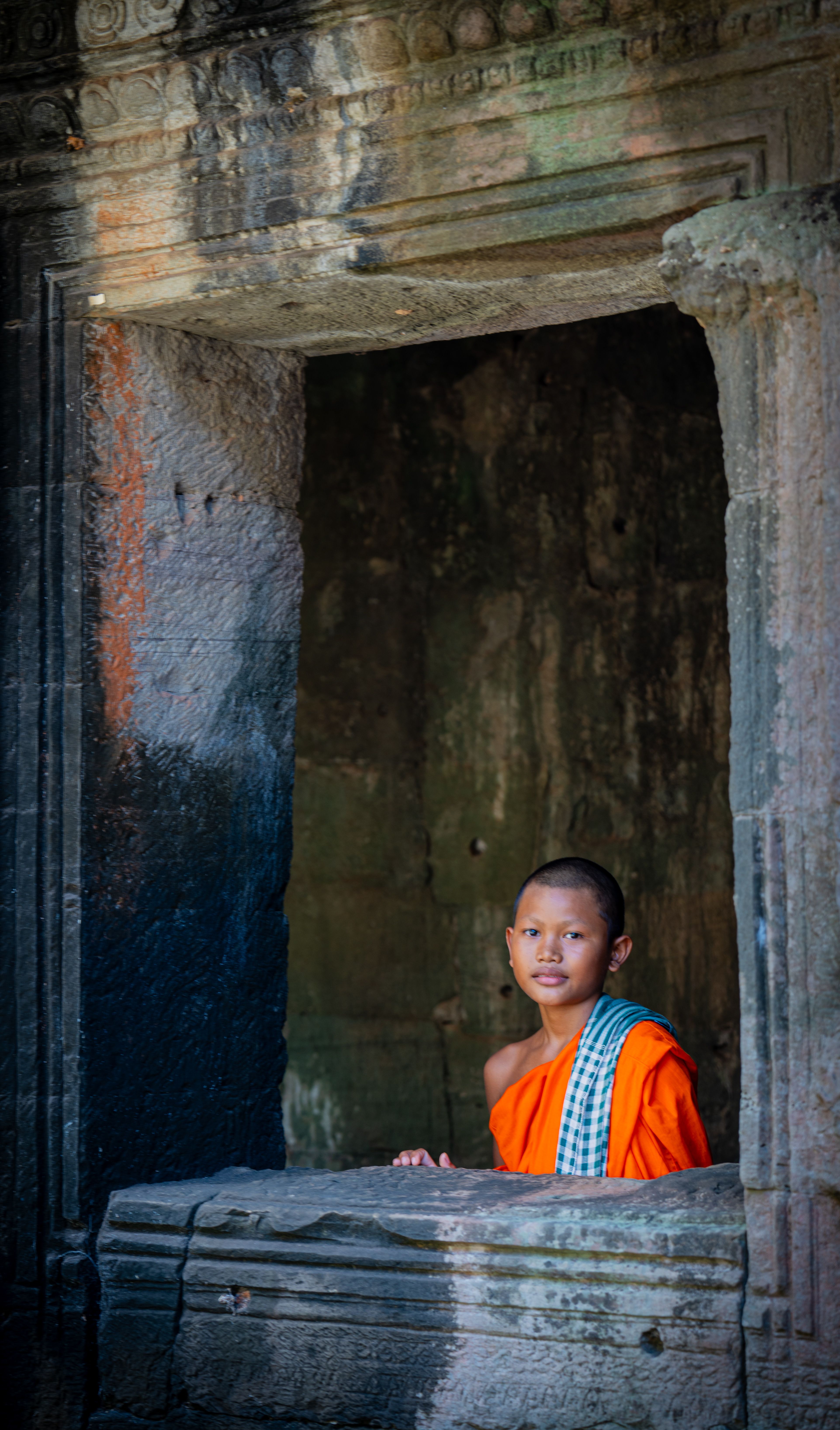 A young monk looking out of a window · Free Stock Photo