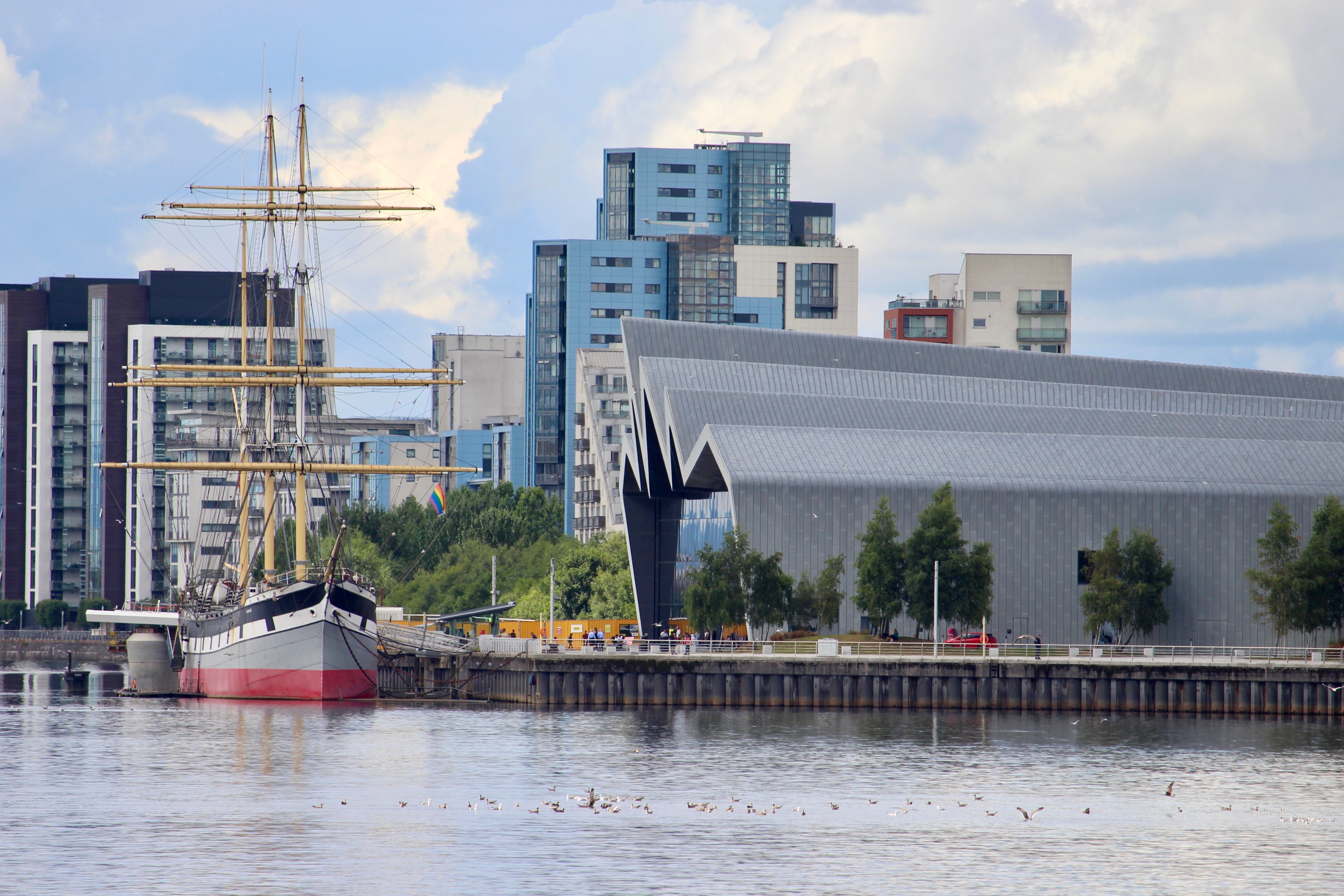 A boat is docked in front of a large building · Free Stock Photo