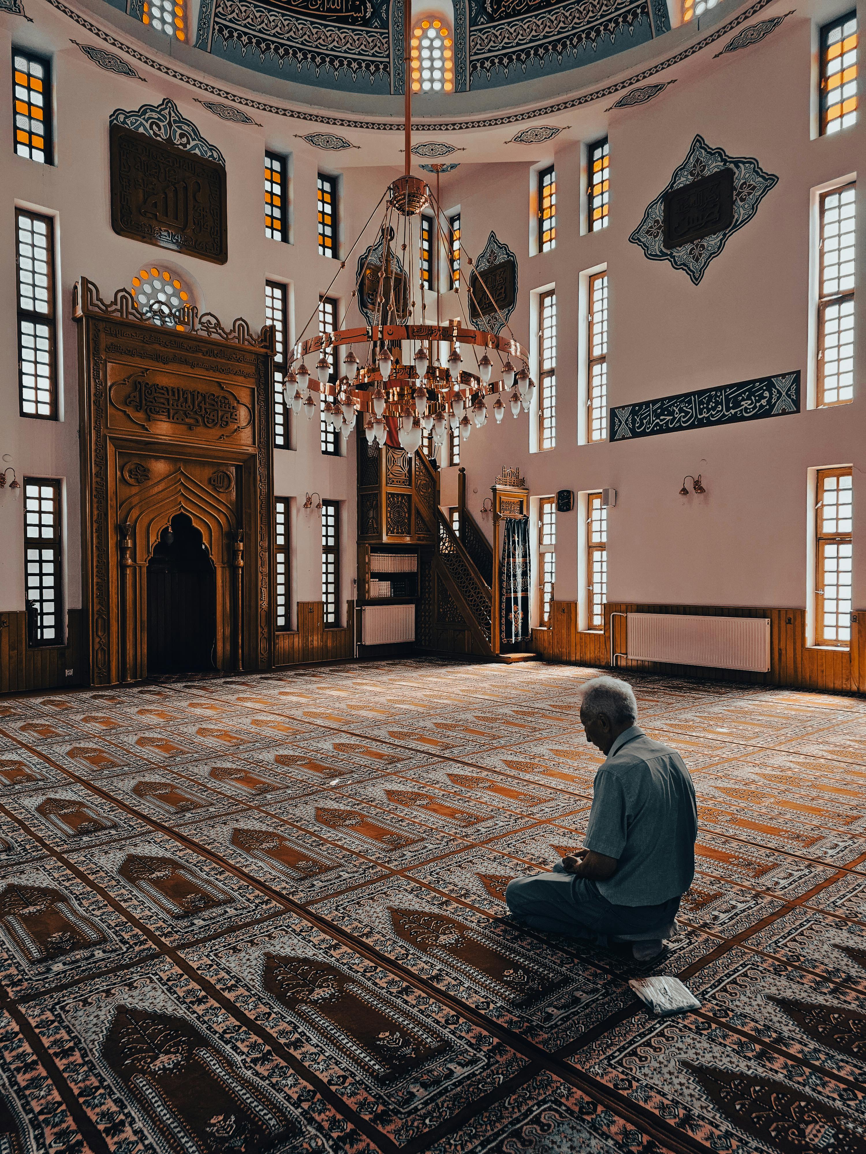 A man sitting on the floor in front of a mosque · Free Stock Photo