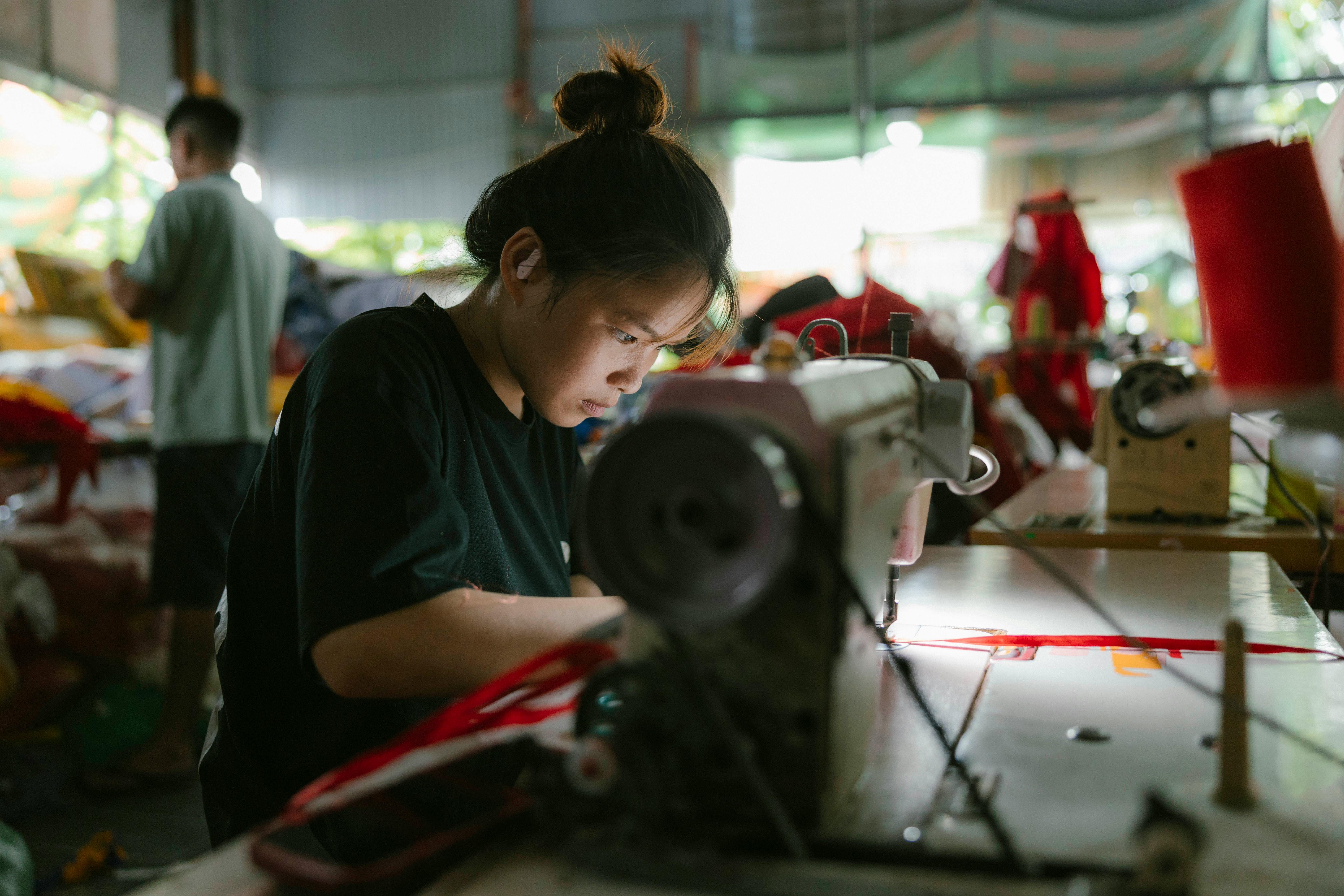 A woman is working on a sewing machine in a factory · Free Stock Photo