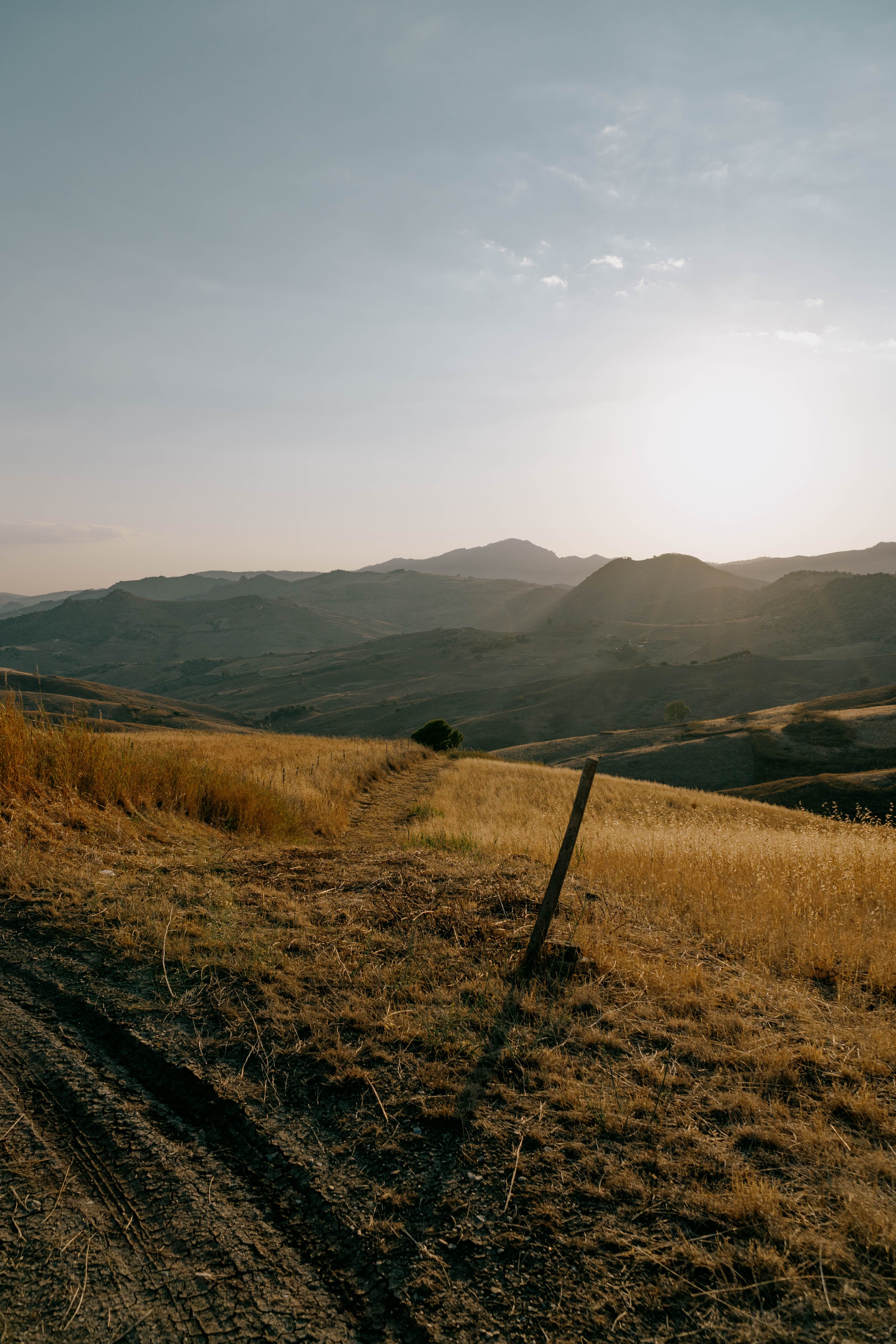 A dirt road leading to a hillside with a sunset in the distance · Free ...