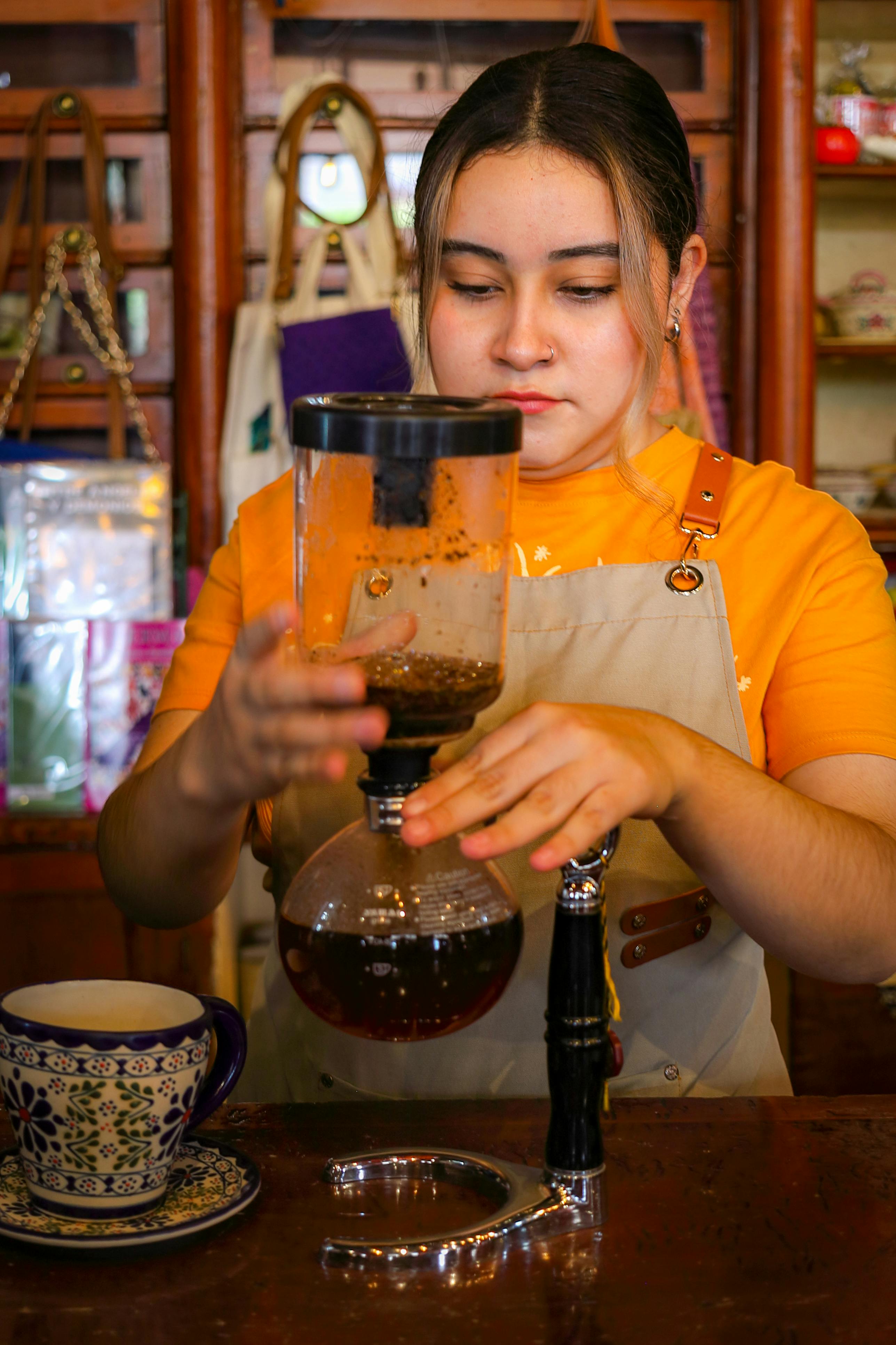 A woman is making coffee in a coffee shop · Free Stock Photo