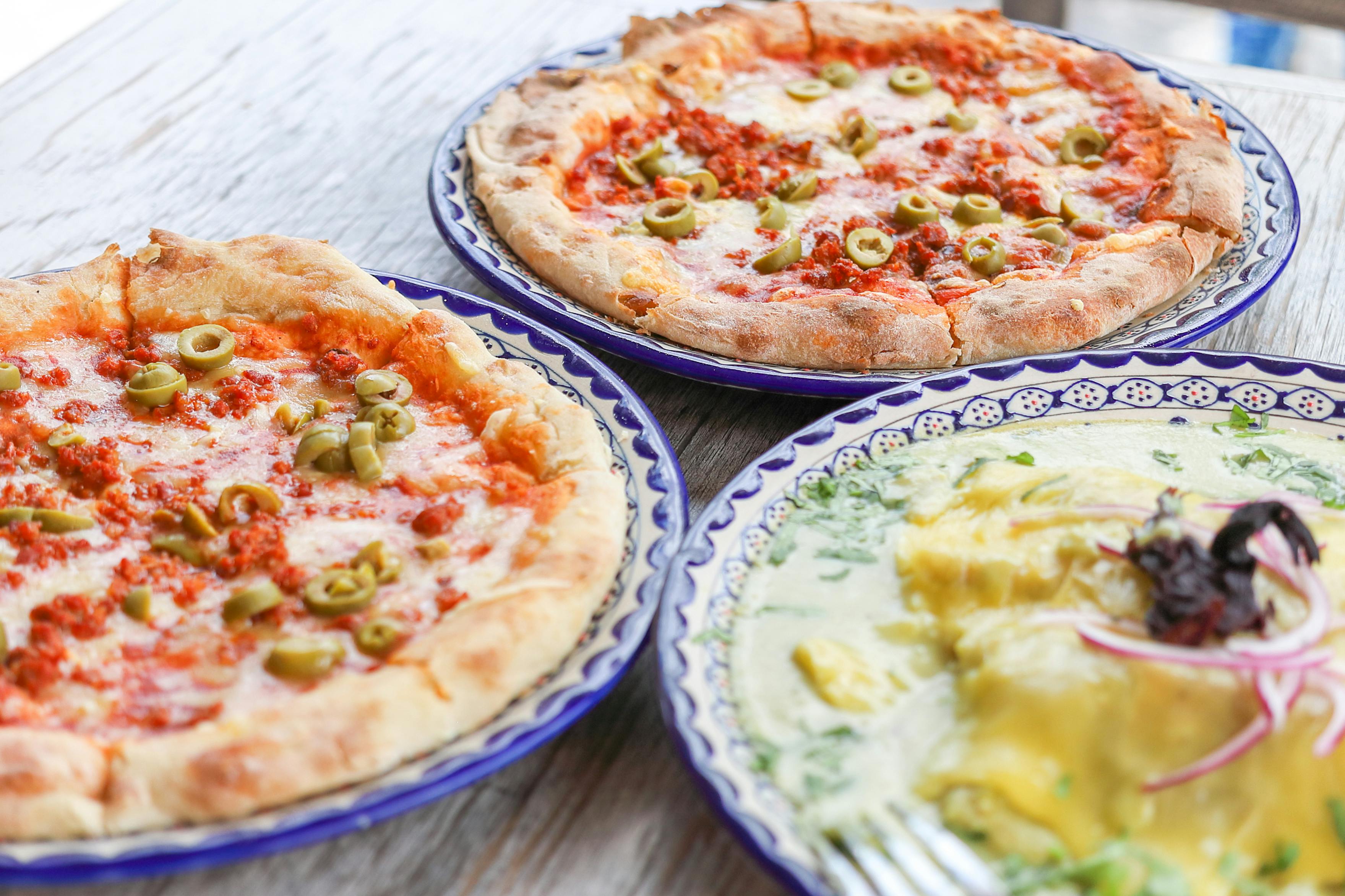 Two plates of pizza with olives and other toppings · Free Stock Photo