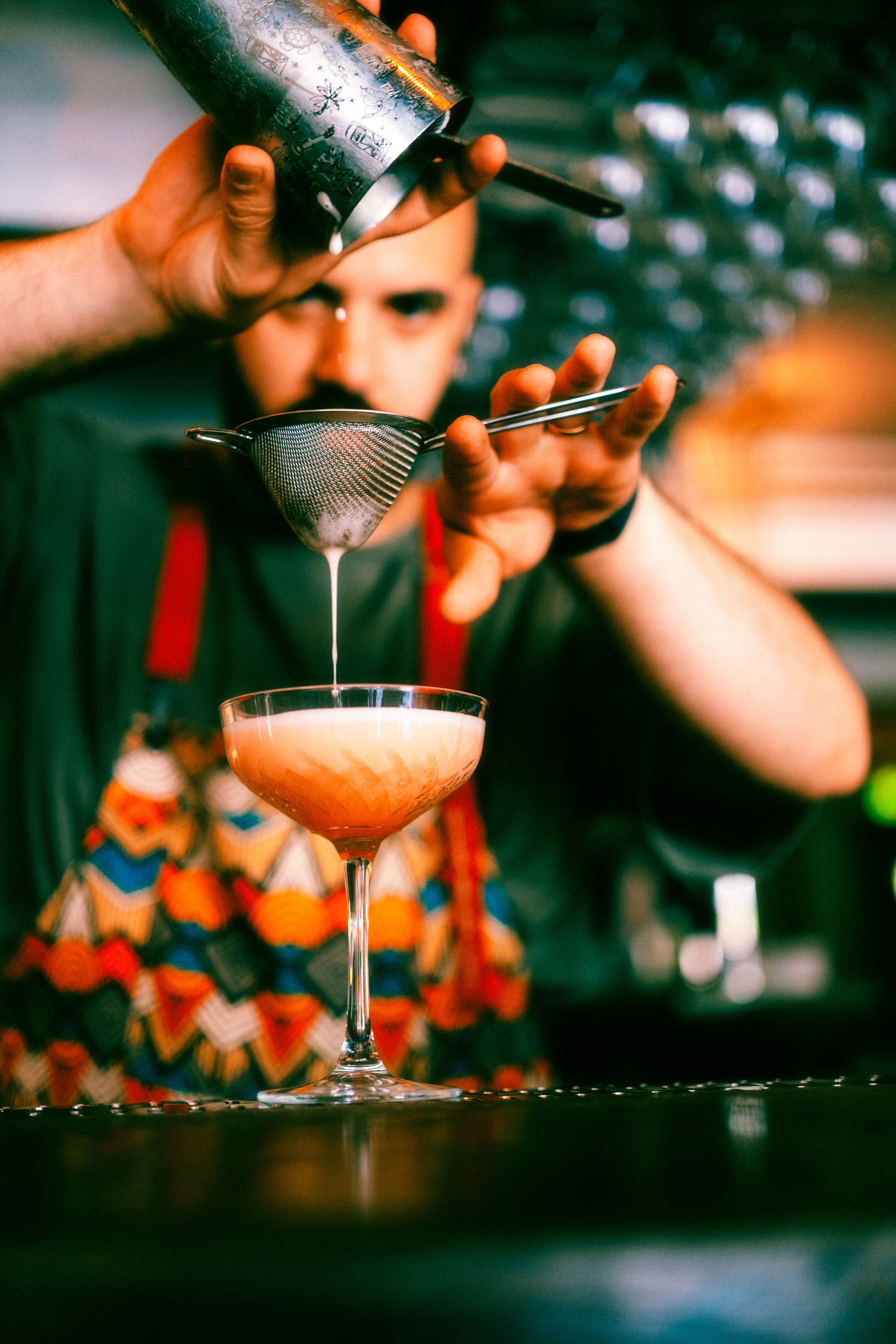 A bartender pouring a cocktail into a glass · Free Stock Photo