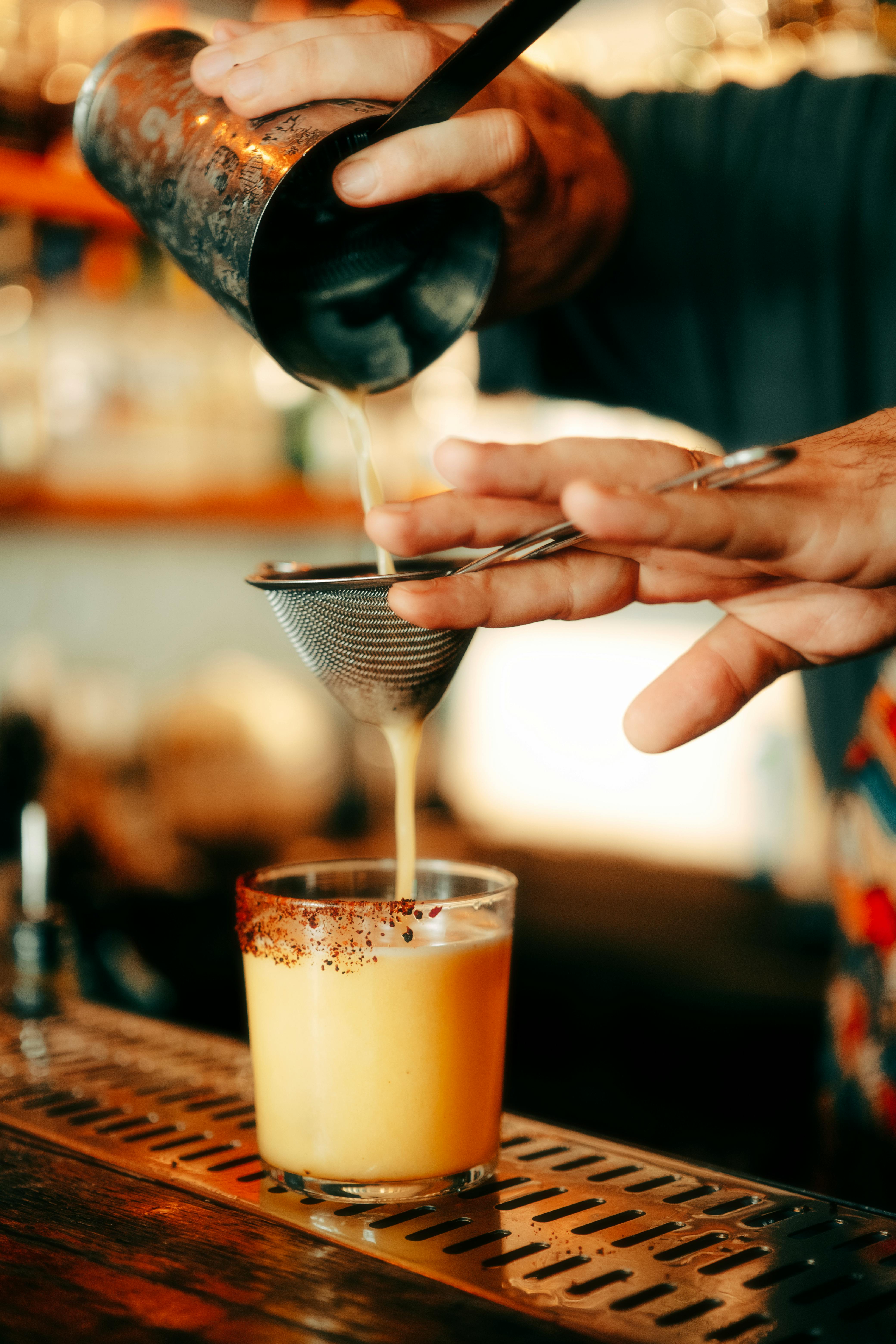 A person pouring a drink into a glass · Free Stock Photo