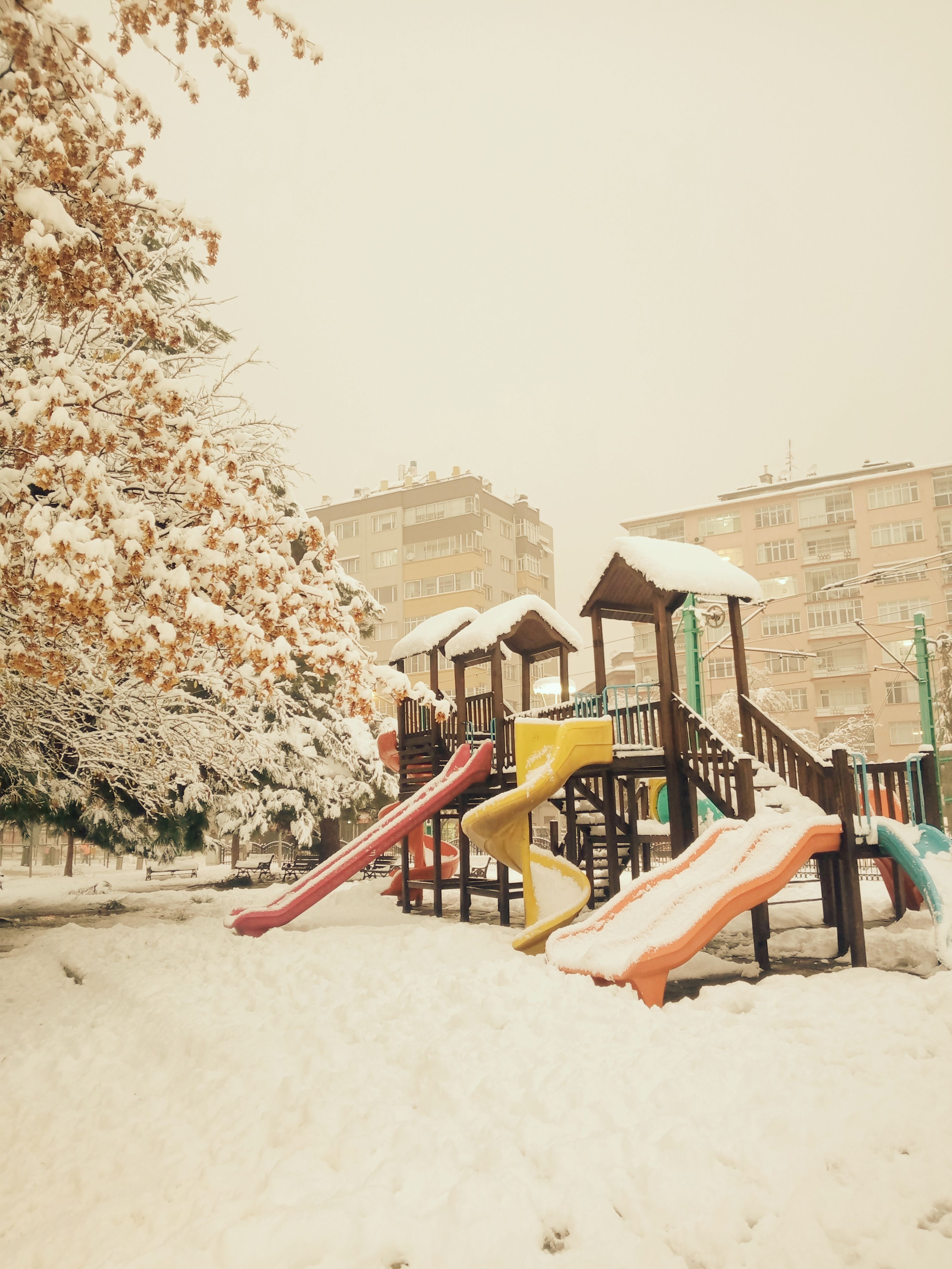 A playground in the snow with a slide and swings · Free Stock Photo