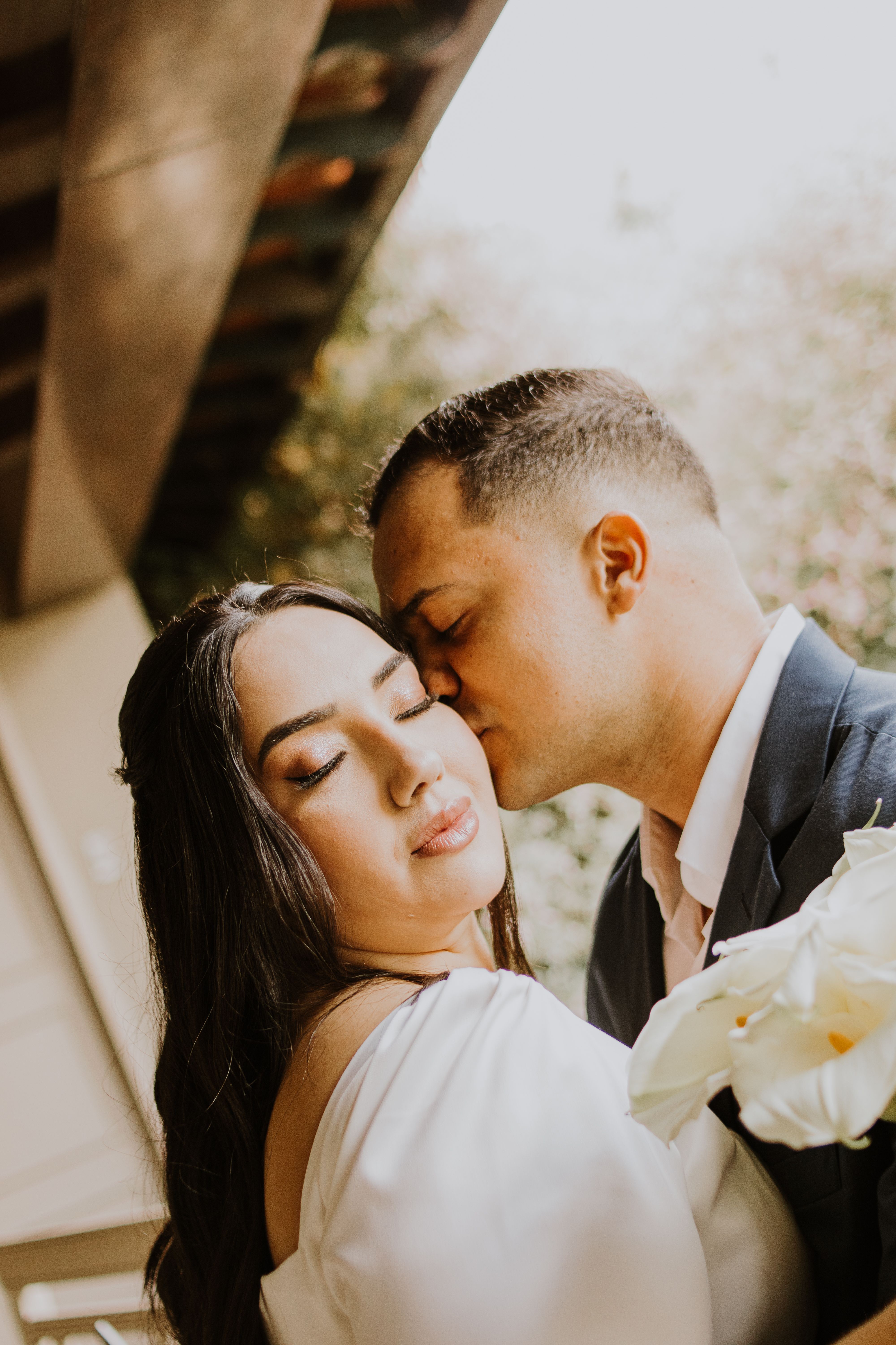 A bride and groom embrace in front of a building · Free Stock Photo