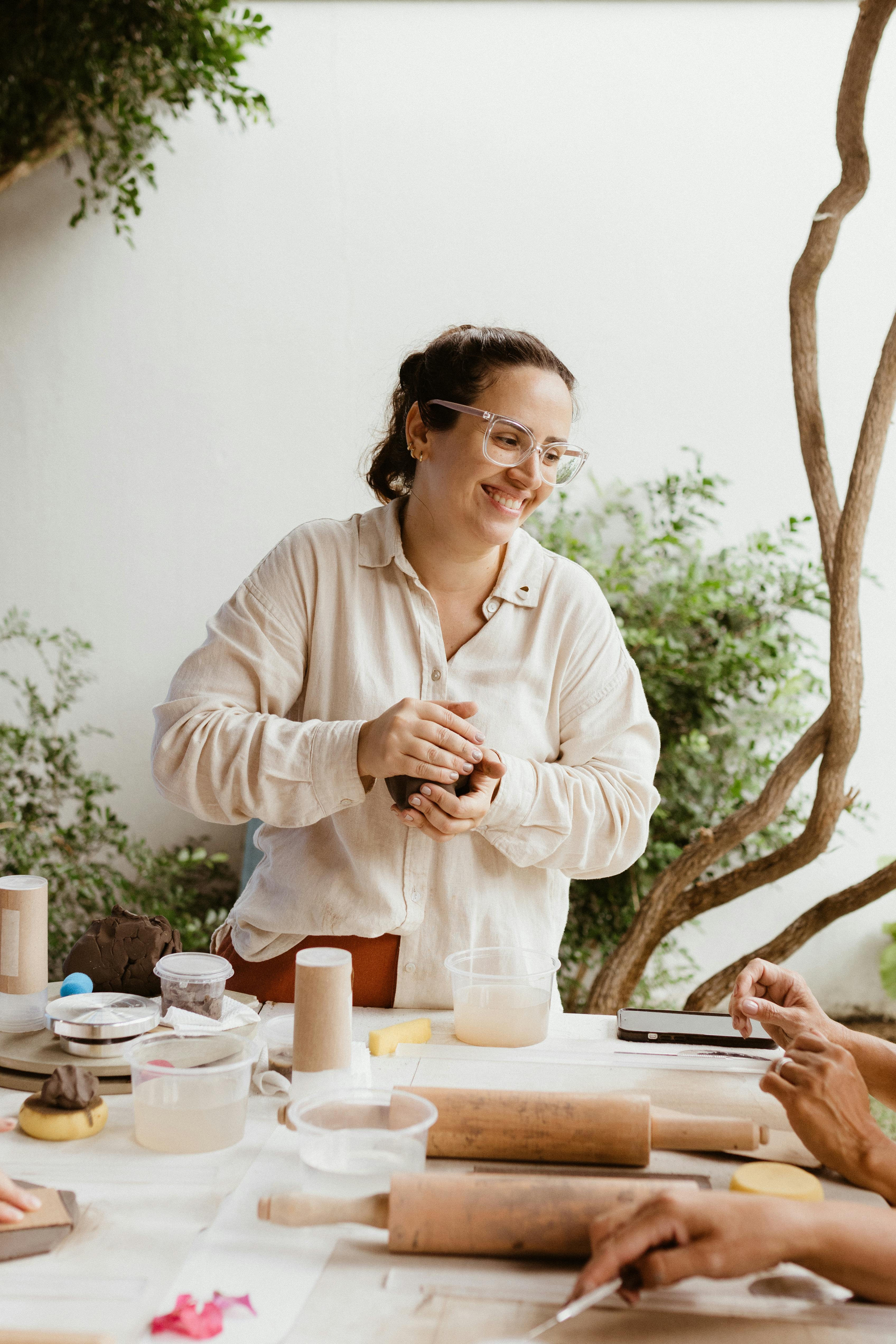 A woman making clay pots at a table · Free Stock Photo