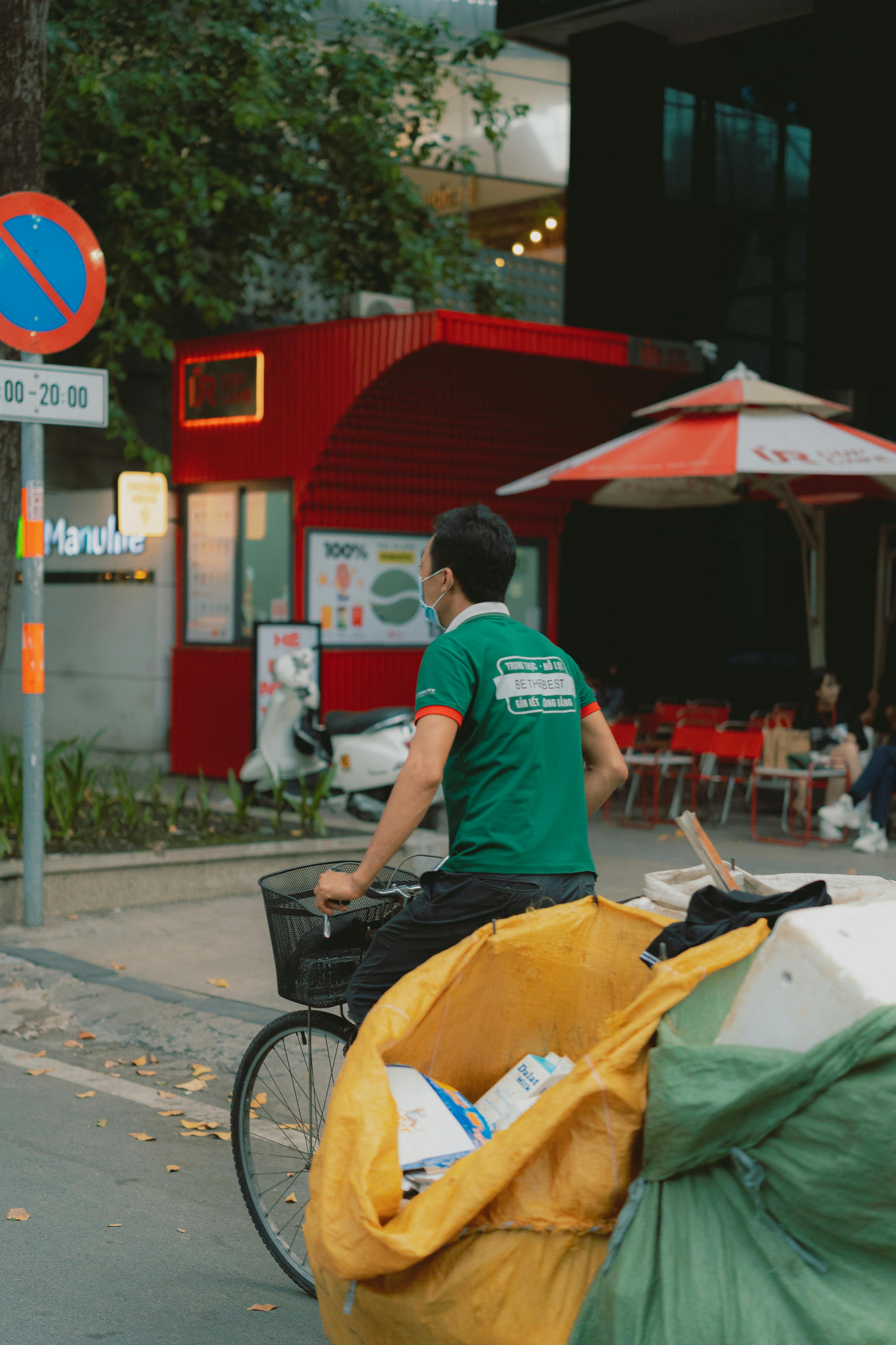 A man on a bicycle with a garbage bag on the back · Free Stock Photo