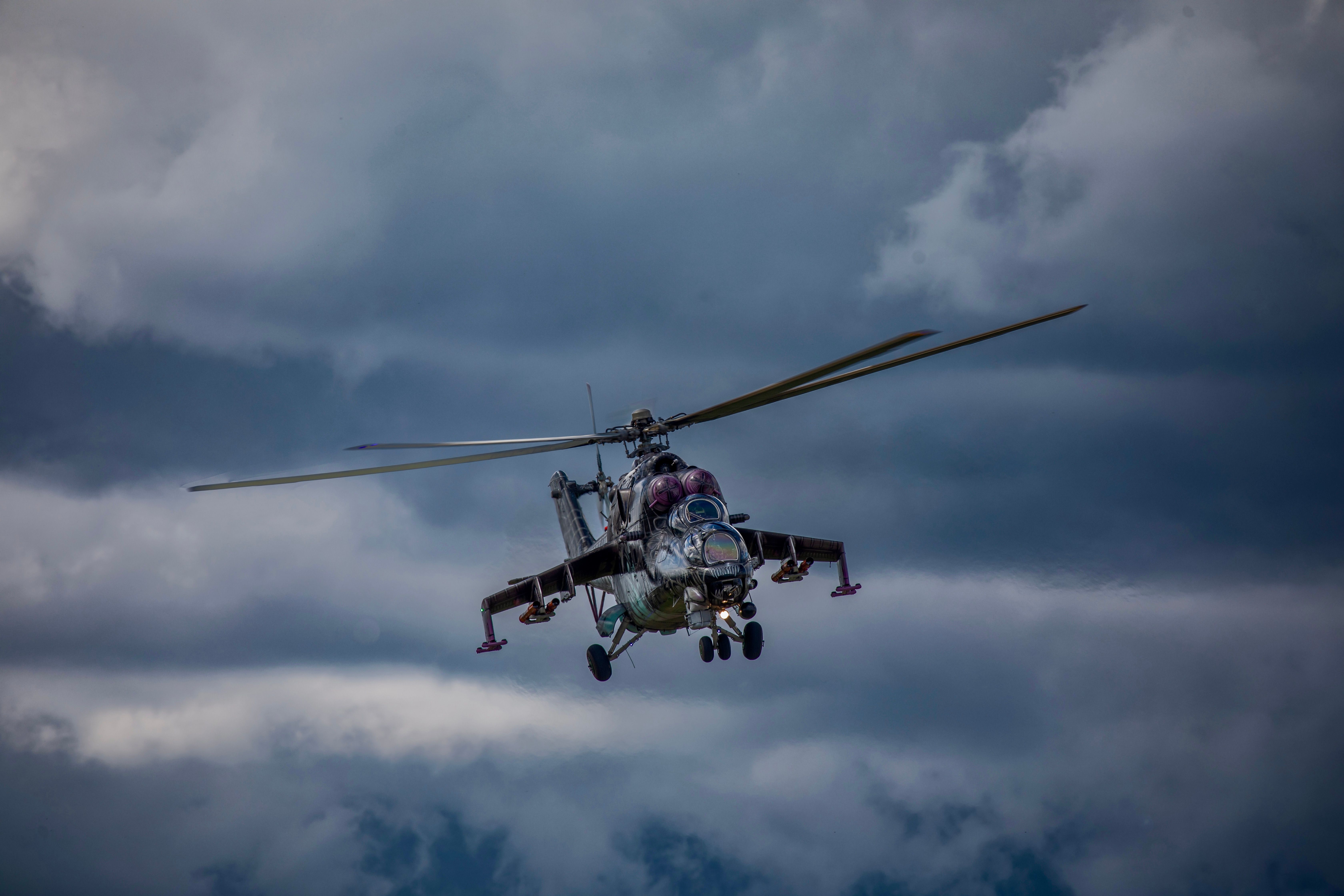 A helicopter flying through the cloudy sky with a large propeller ...