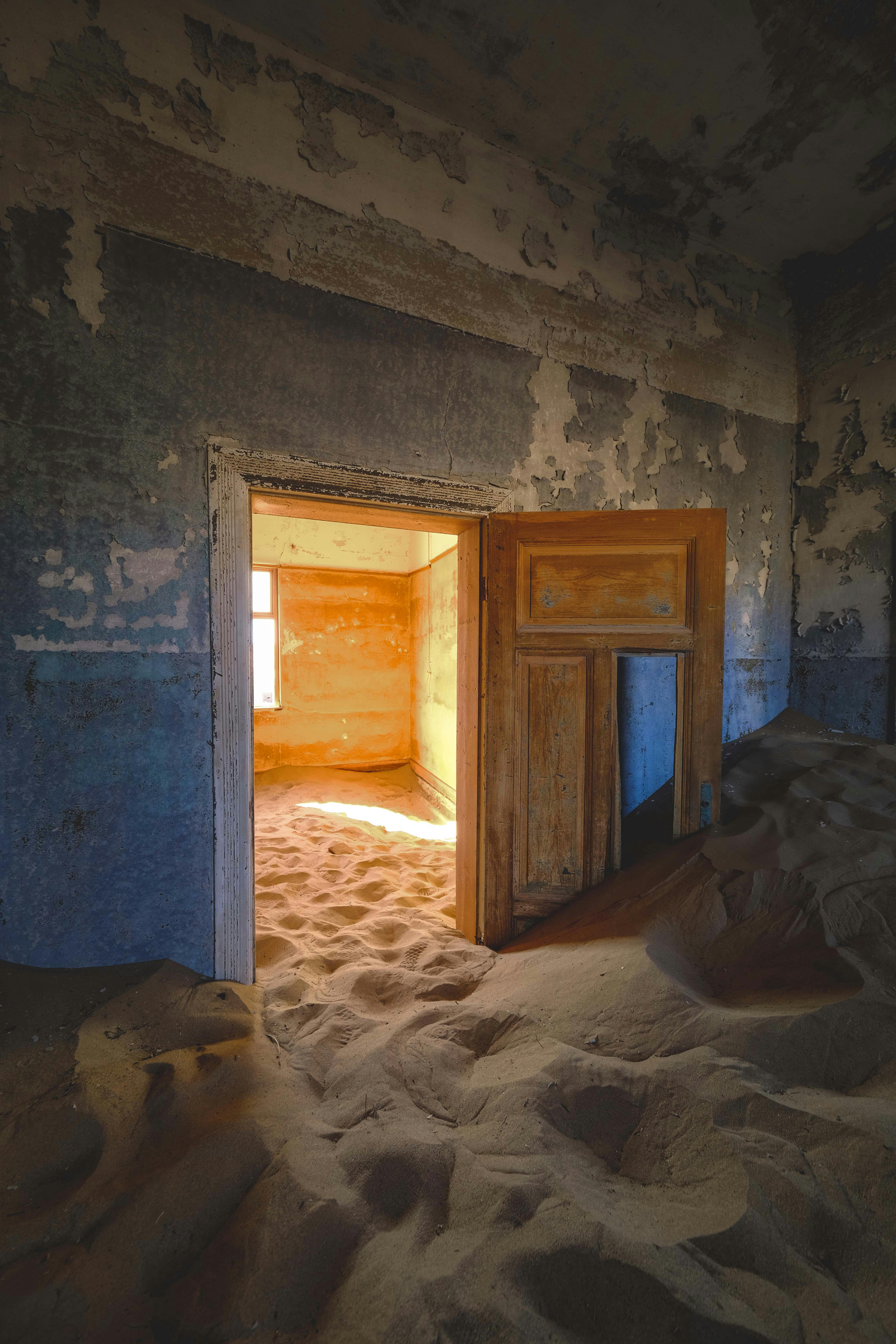 An old door in a desert with sand on the floor · Free Stock Photo