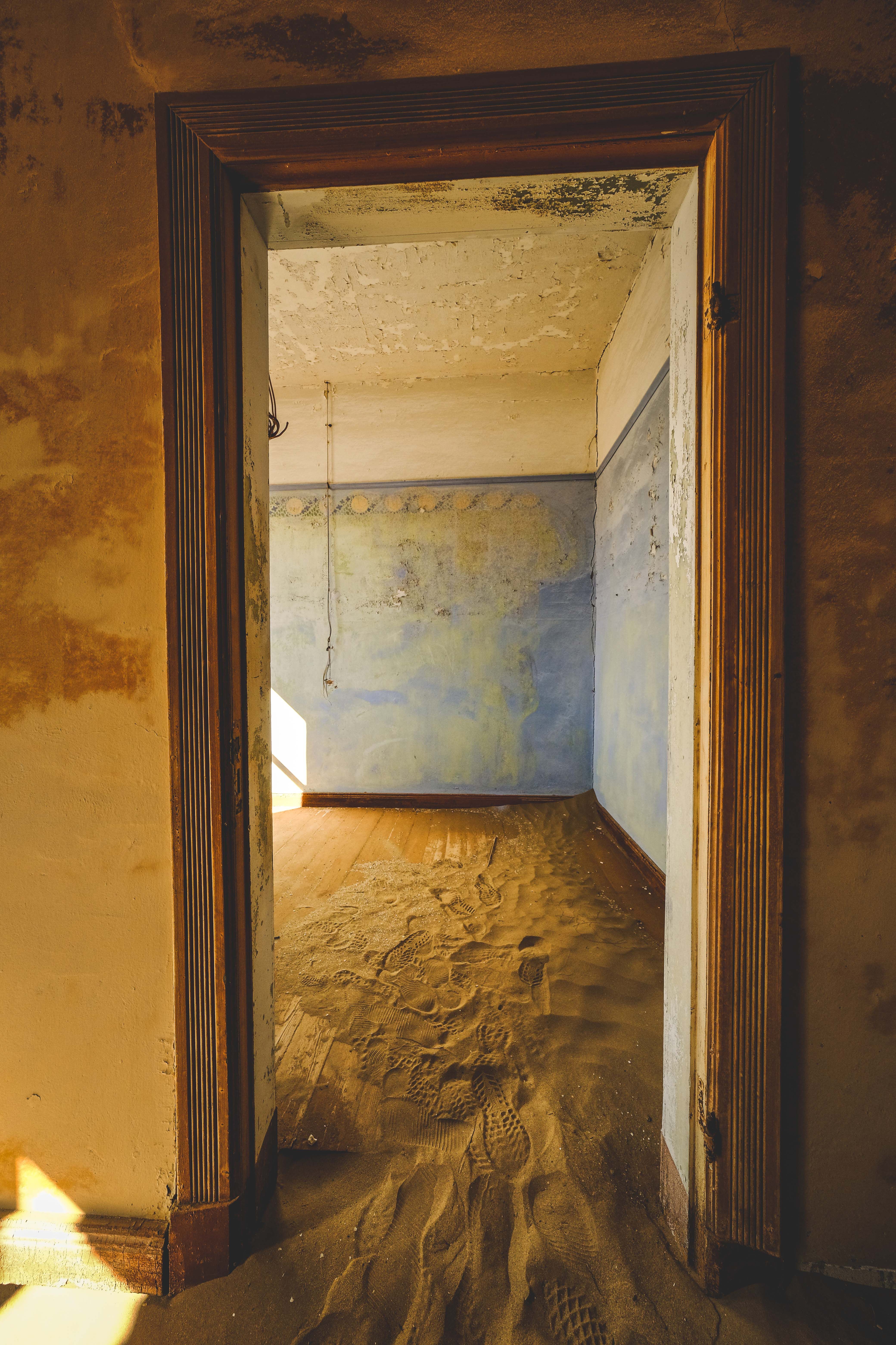 An open door in an old building with sand on the floor · Free Stock Photo