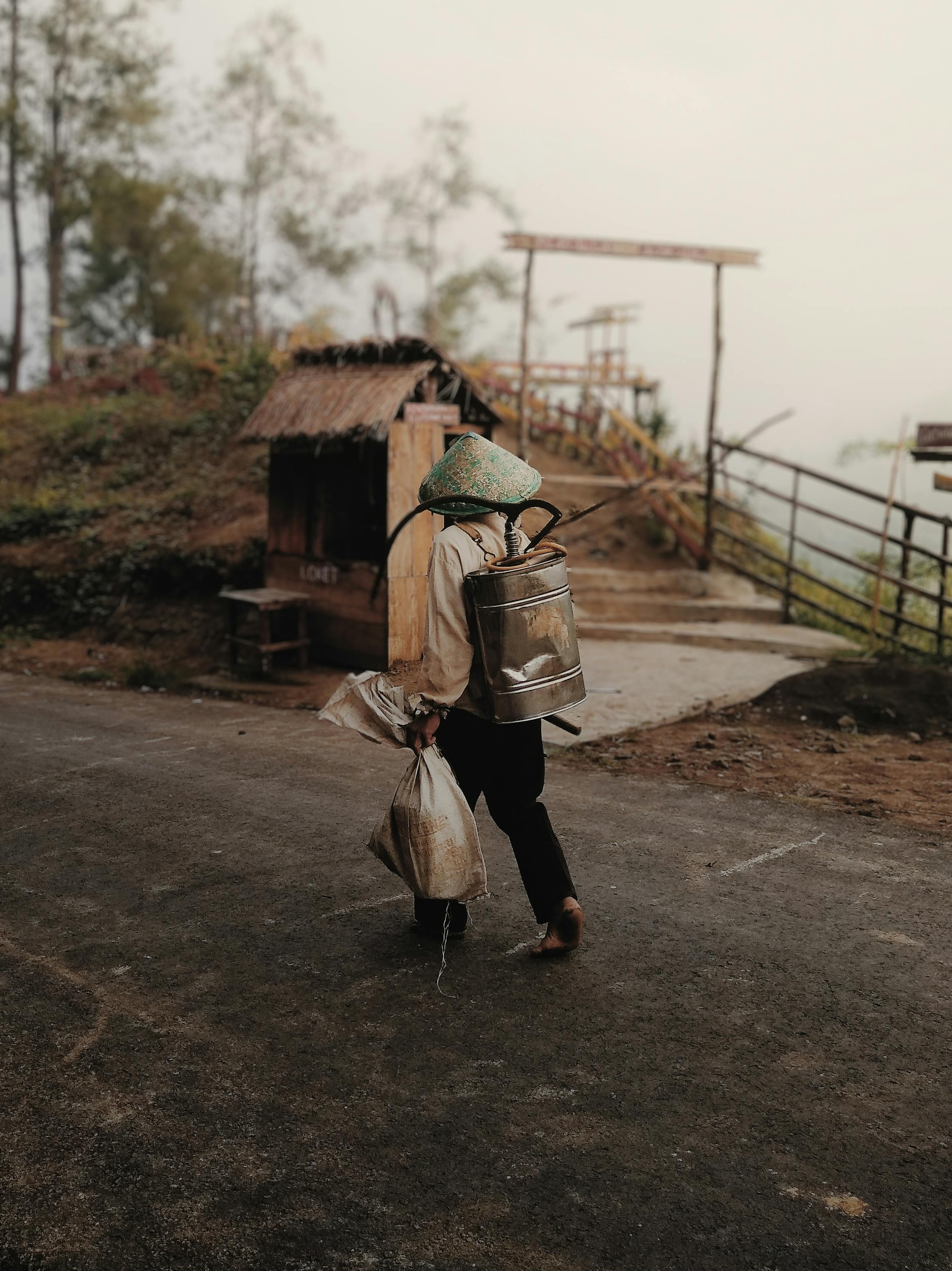 Person in Conical Hat Carrying Keg on Road · Free Stock Photo