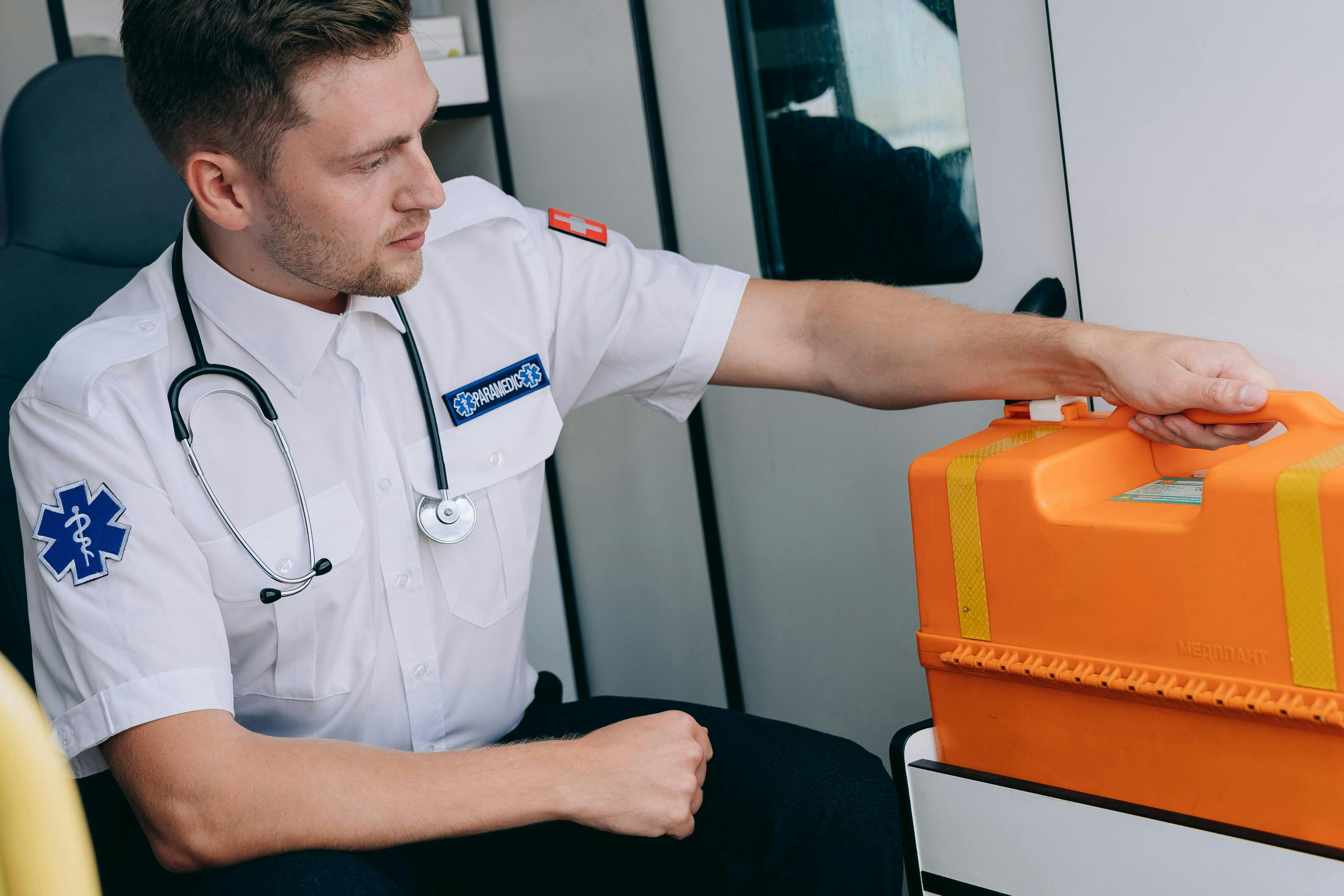 Paramedic Holding Orange AID Suitcase in Ambulance · Free Stock Photo