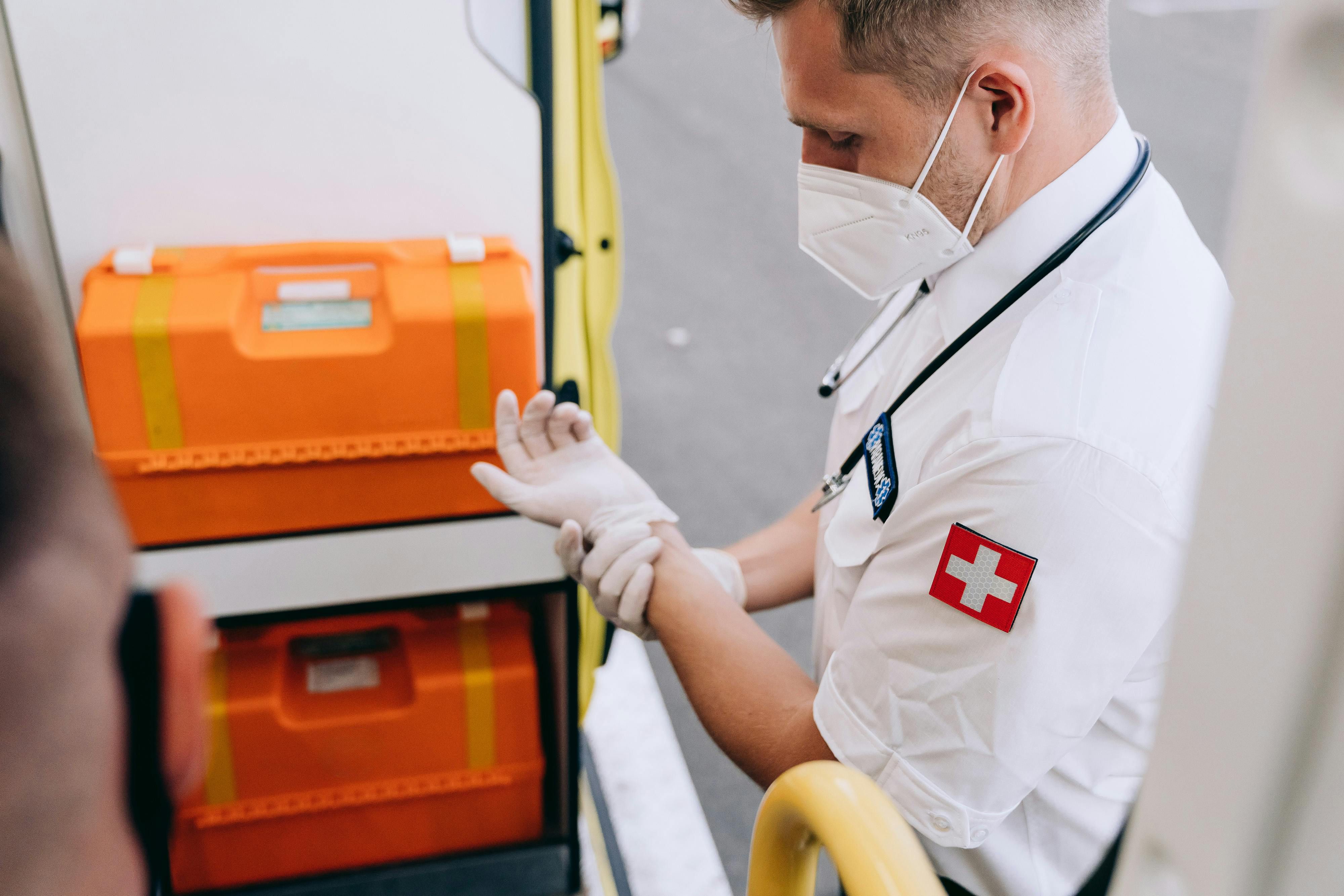 Paramedic in Face Mask Putting On Rubber Gloves · Free Stock Photo