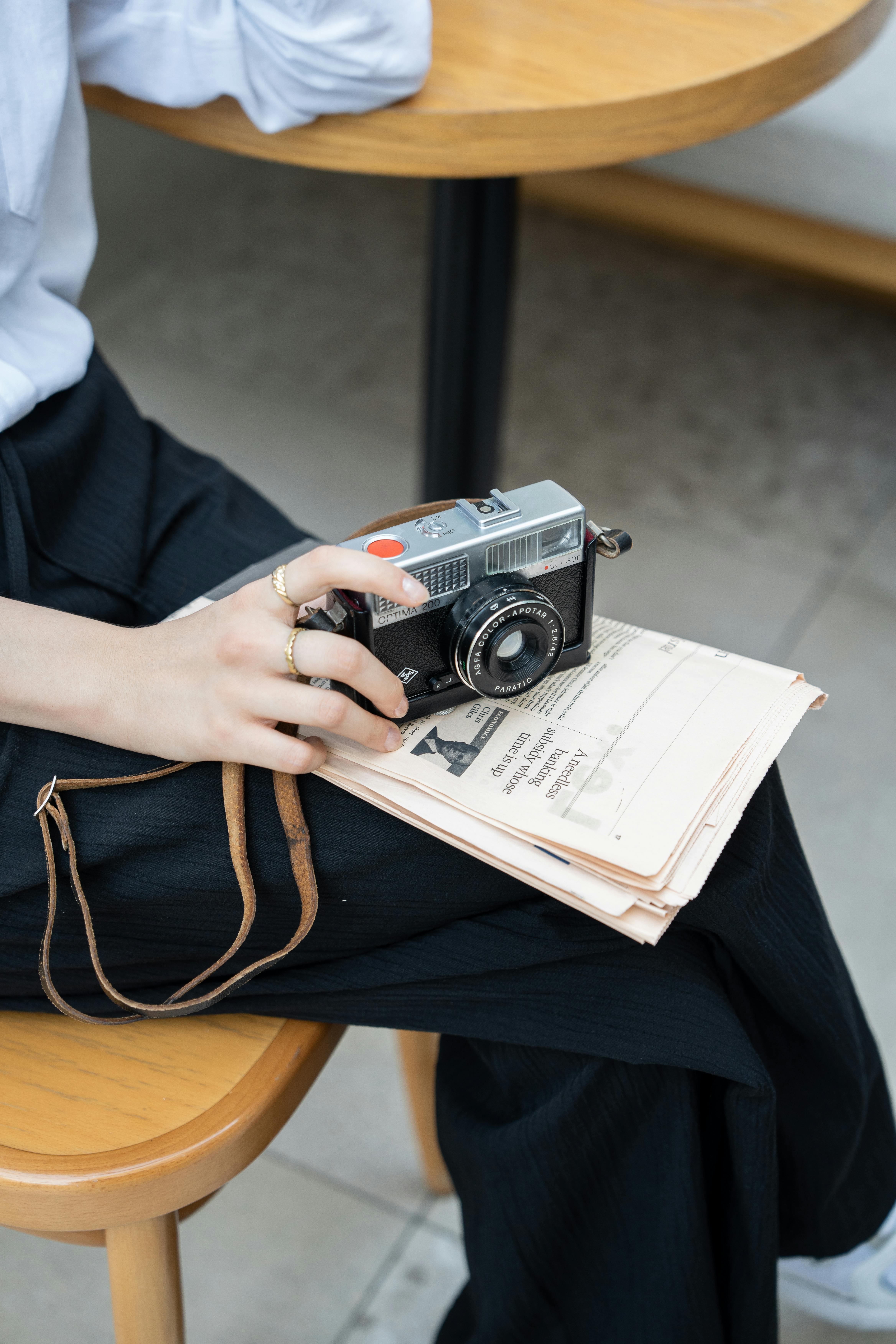 A woman holding a camera and reading a newspaper · Free Stock Photo