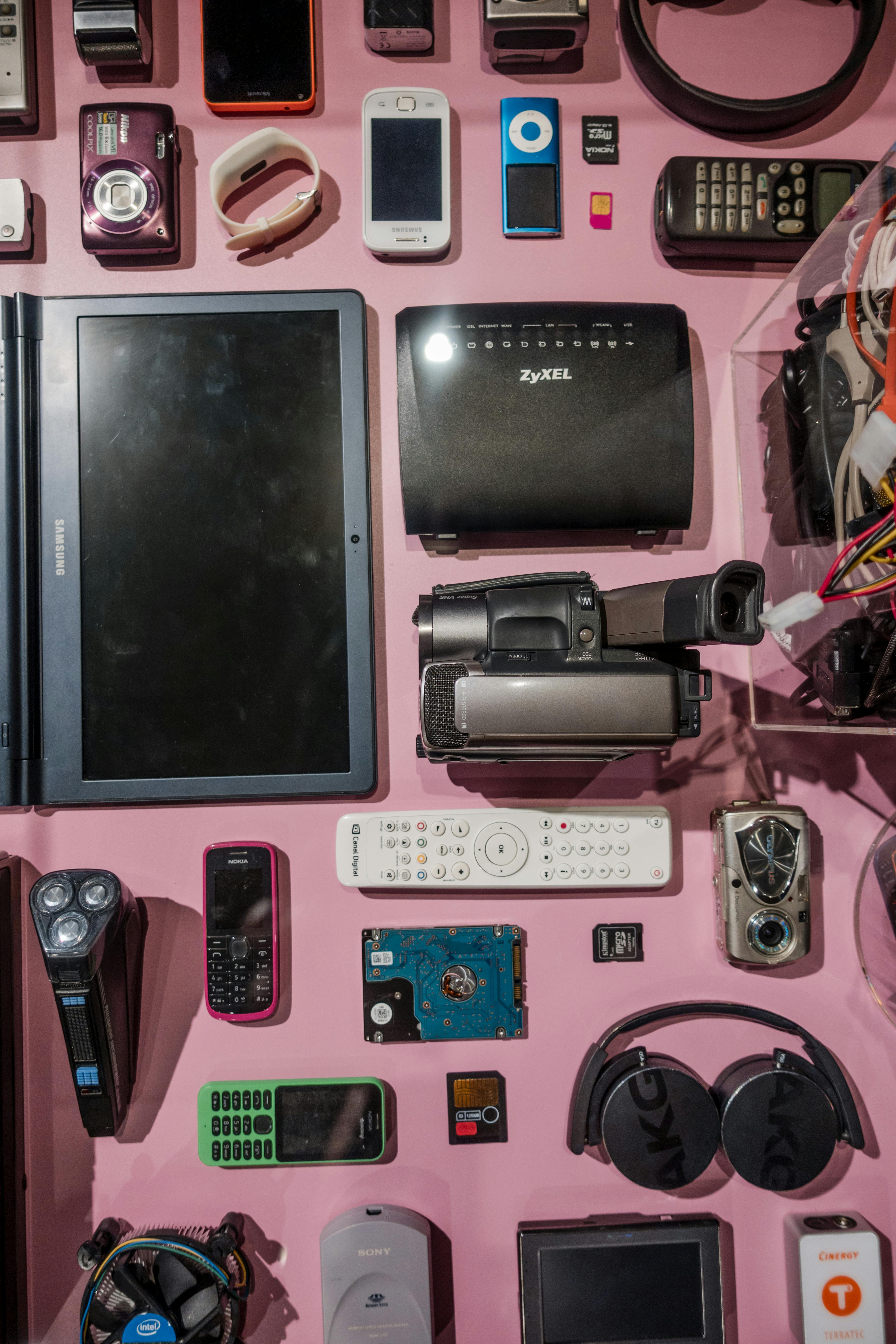 A pink background with various electronic devices and accessories ...