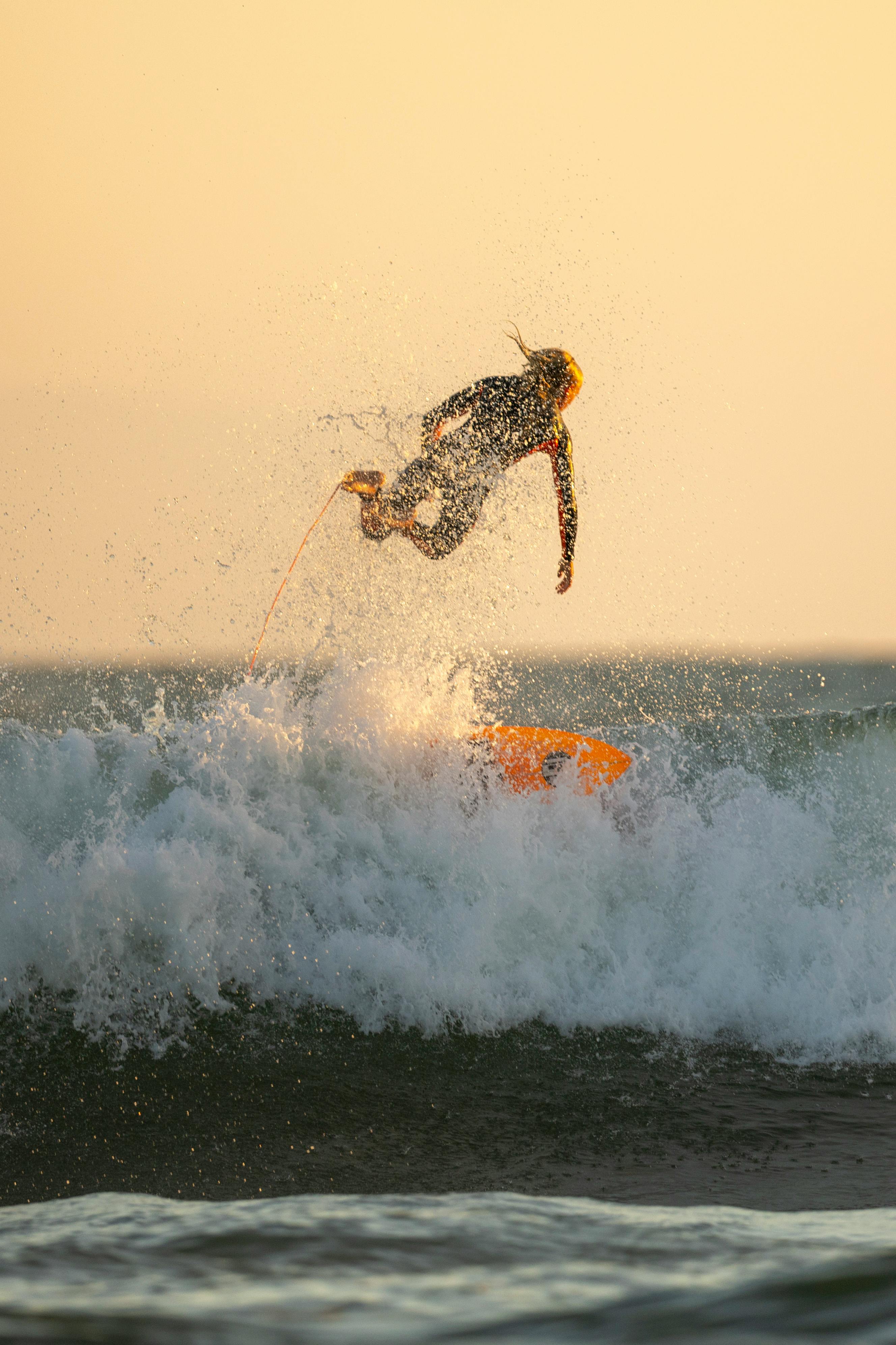 A surfer is jumping off of a surfboard in the ocean · Free Stock Photo
