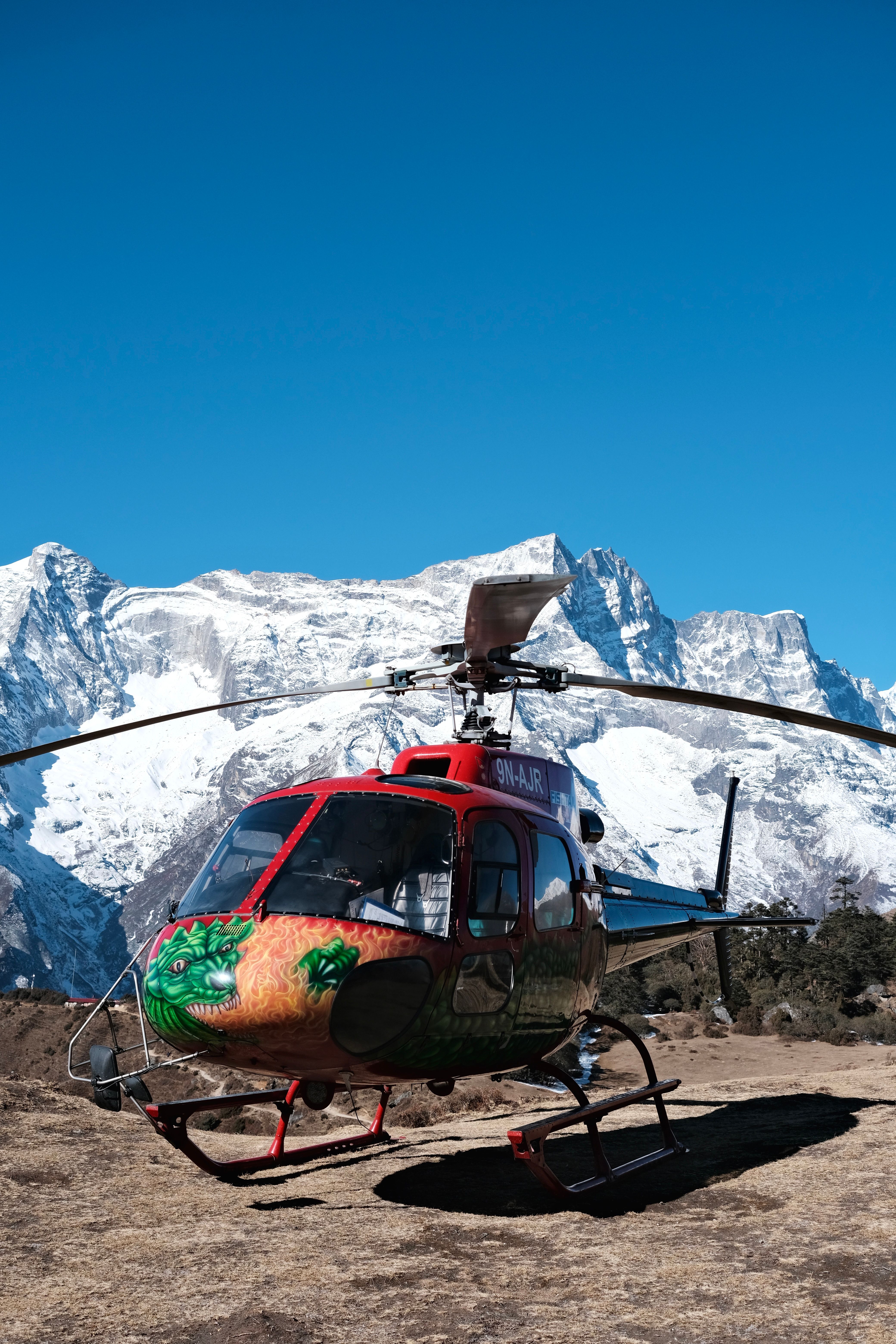 A helicopter is parked on a grassy field with mountains in the ...