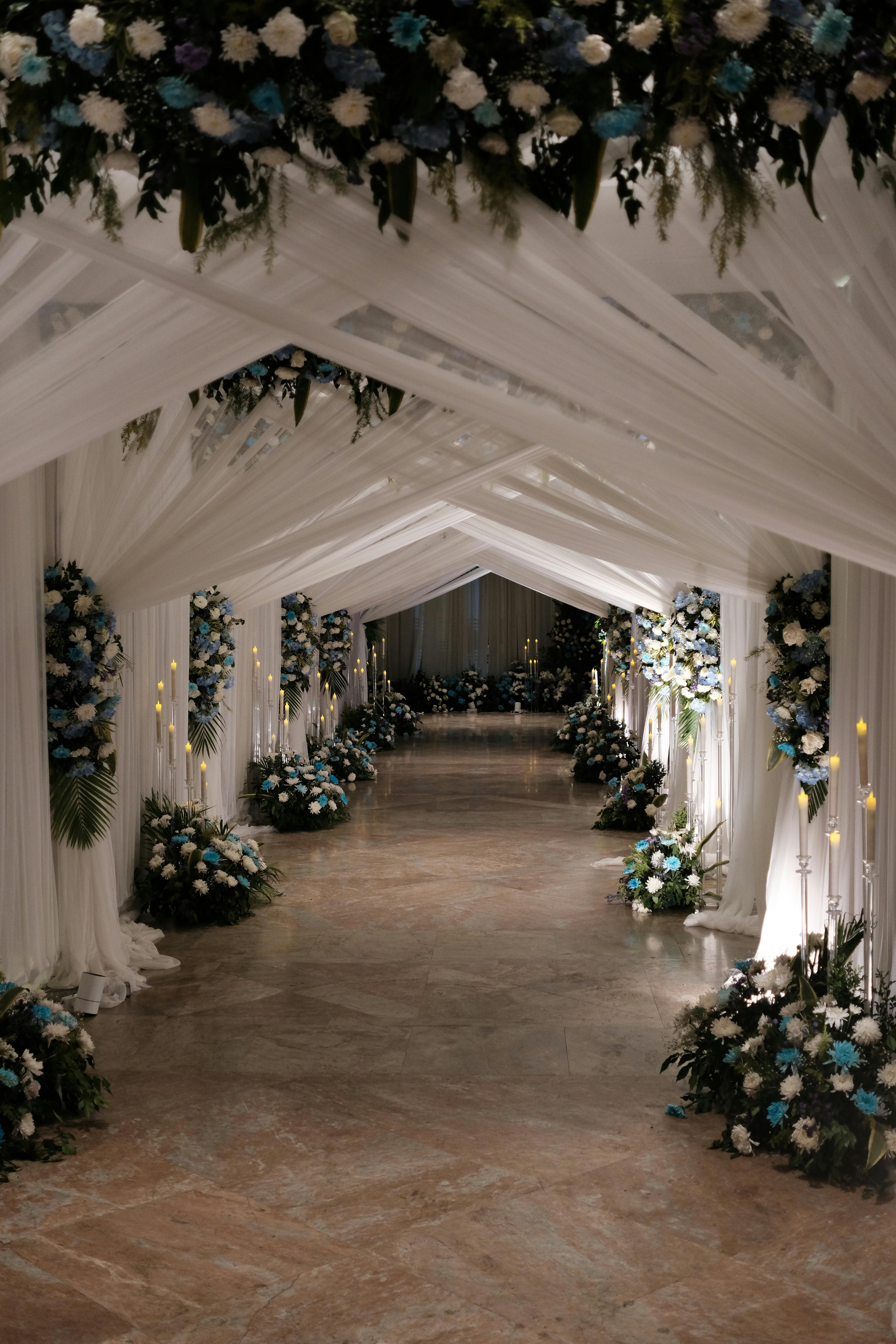 A long aisle with white flowers and blue garlands · Free Stock Photo