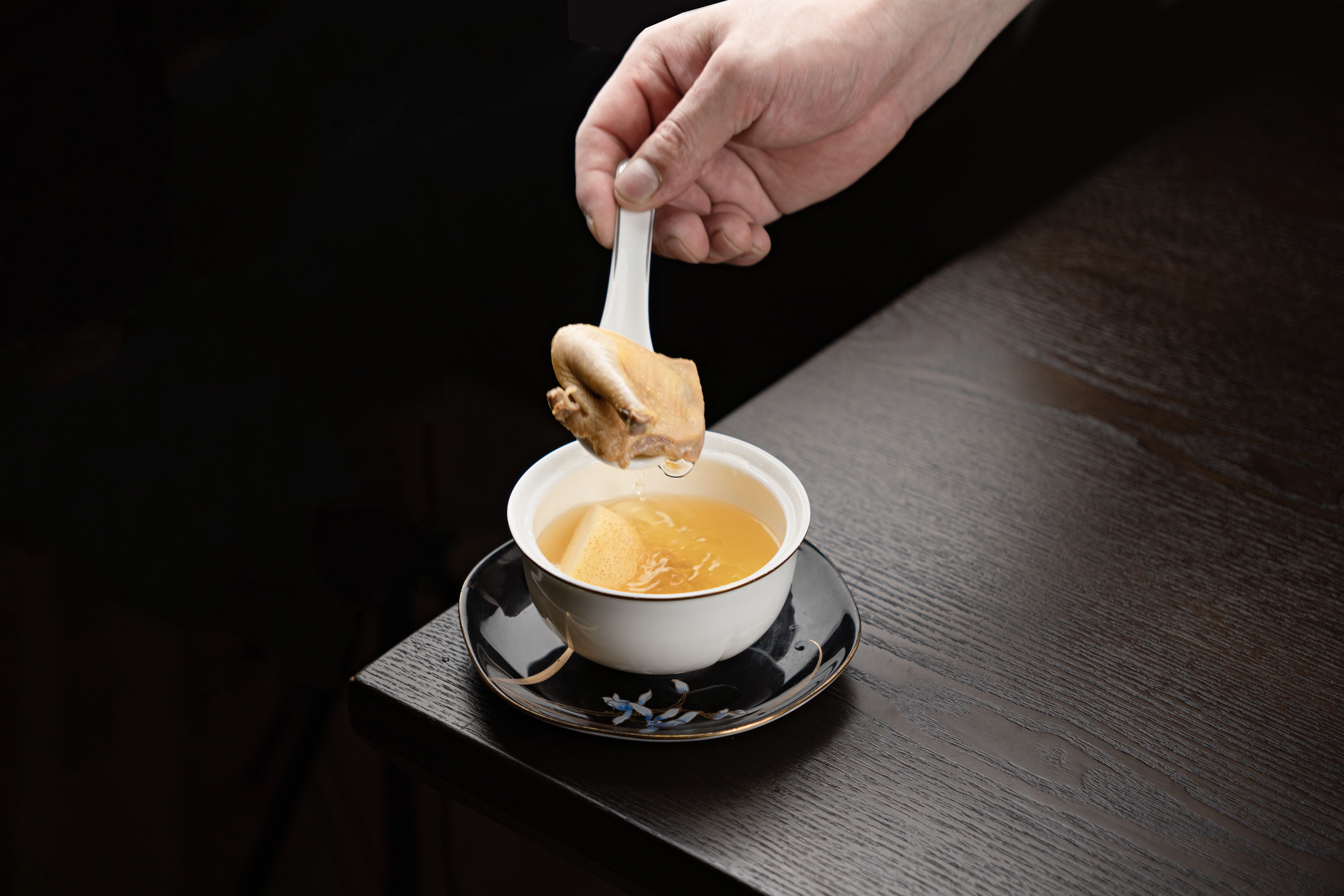 A person is holding a spoon over a cup of tea · Free Stock Photo