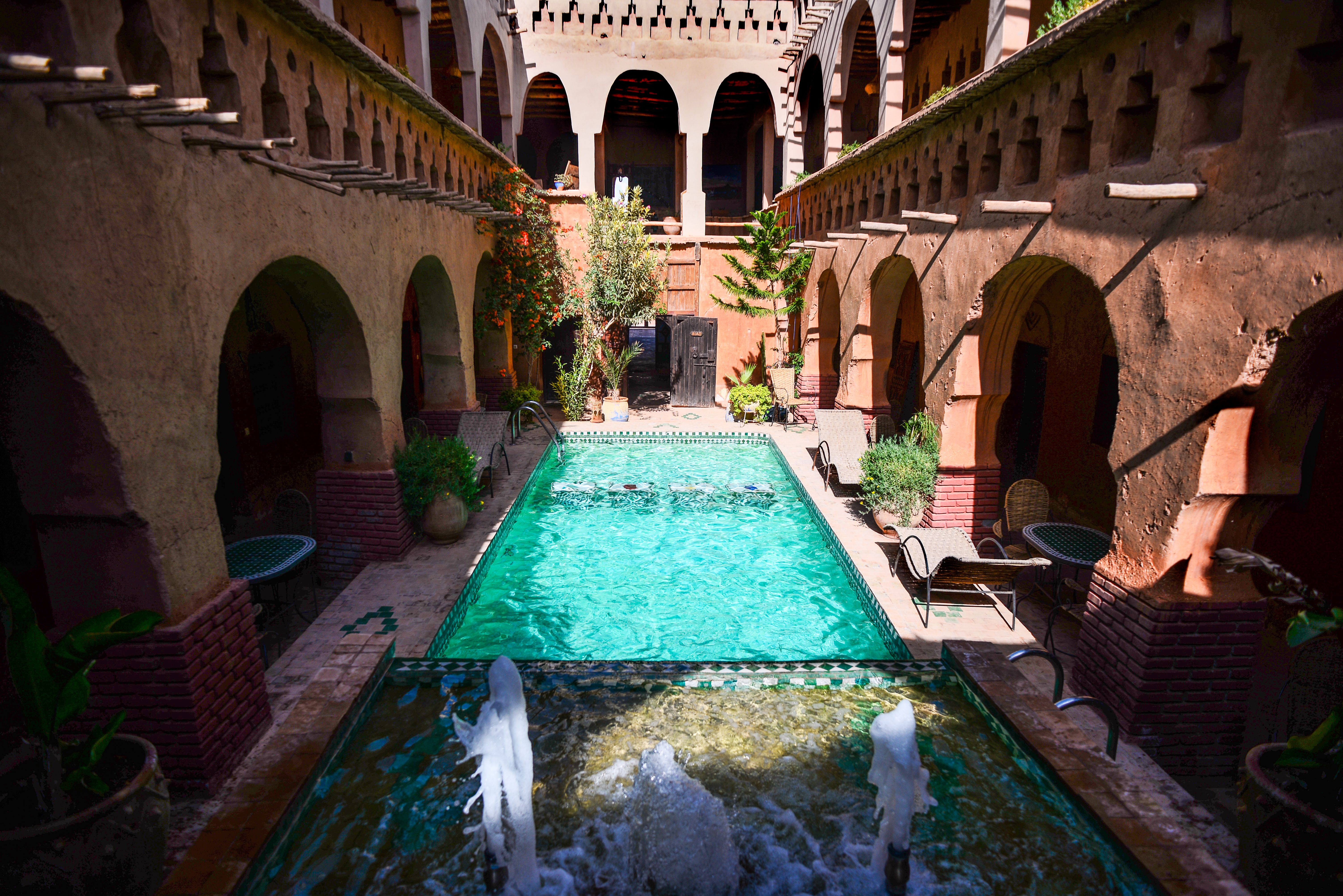 A courtyard with a pool and fountain in the middle · Free Stock Photo