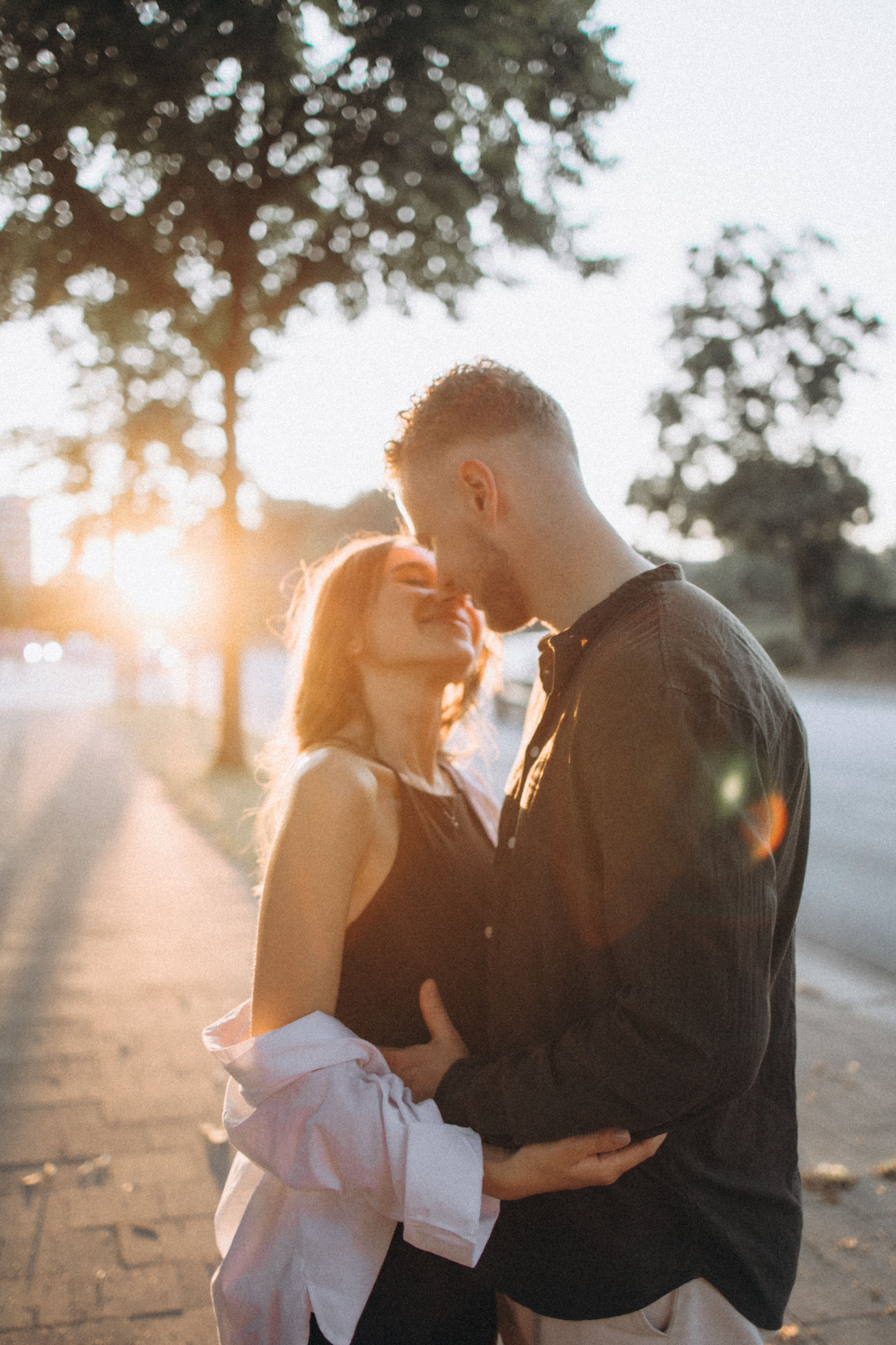 A couple kissing in the sun on a street · Free Stock Photo
