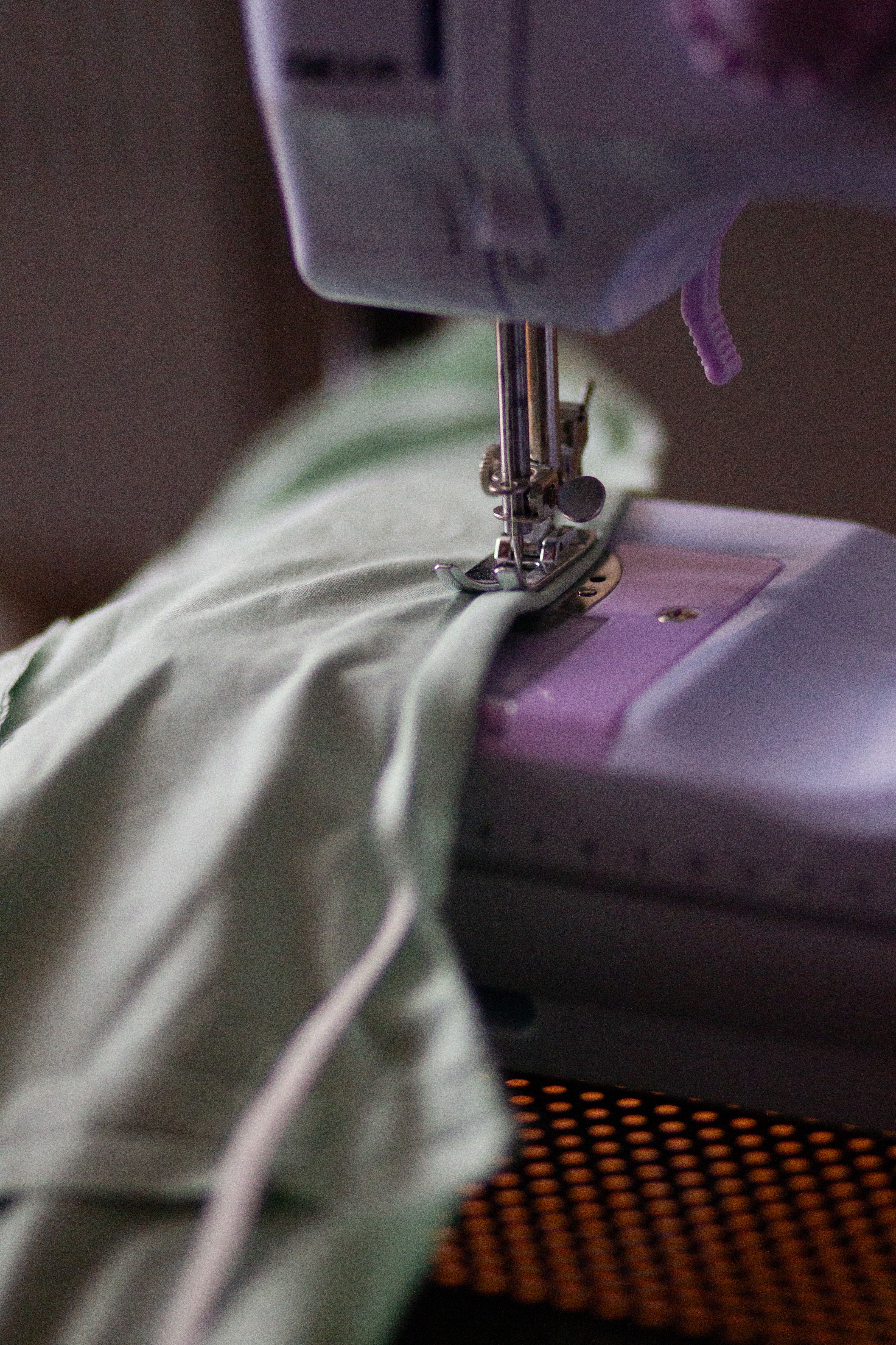 A sewing machine is sewing a green shirt · Free Stock Photo