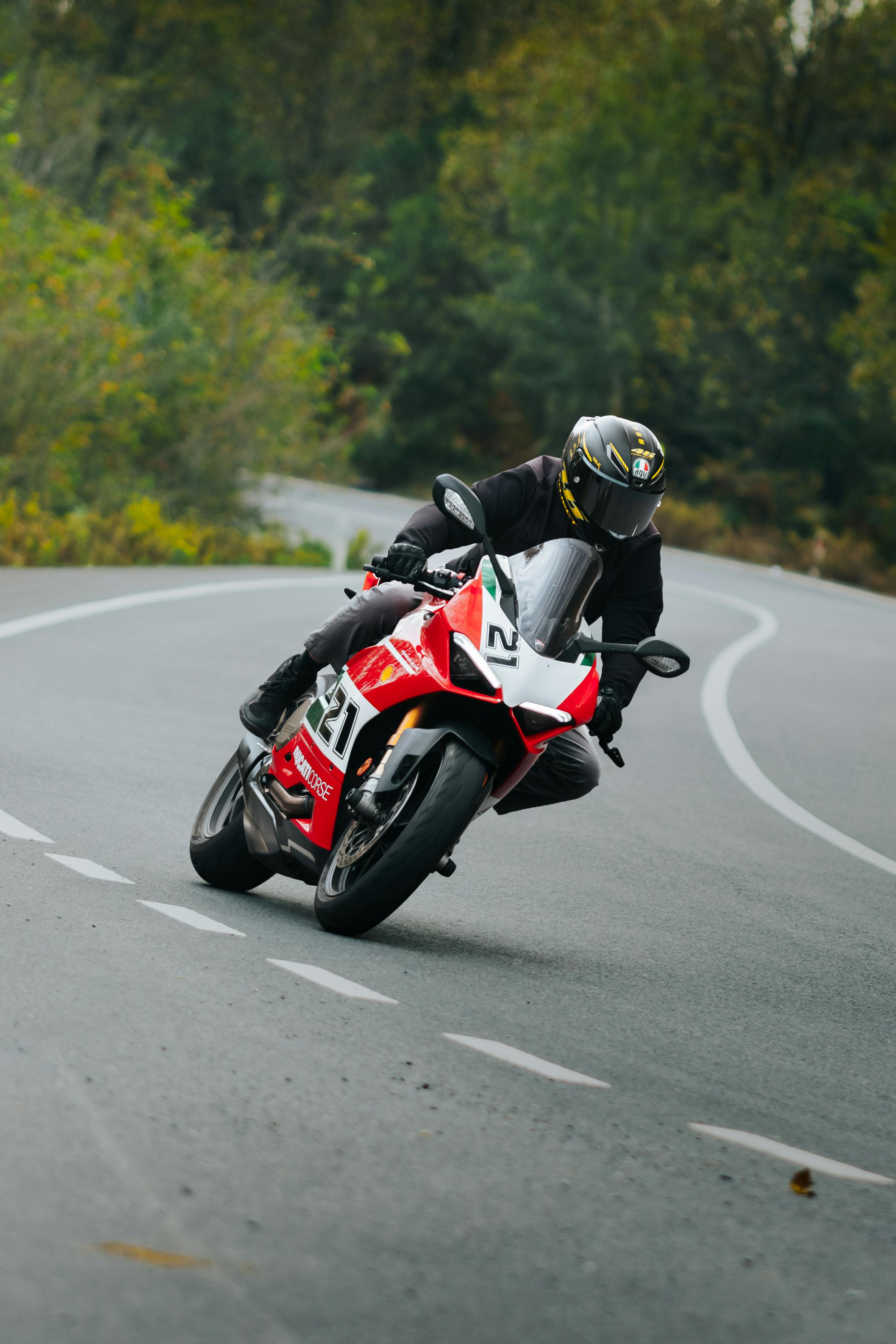 A person riding a motorcycle down a curvy road · Free Stock Photo