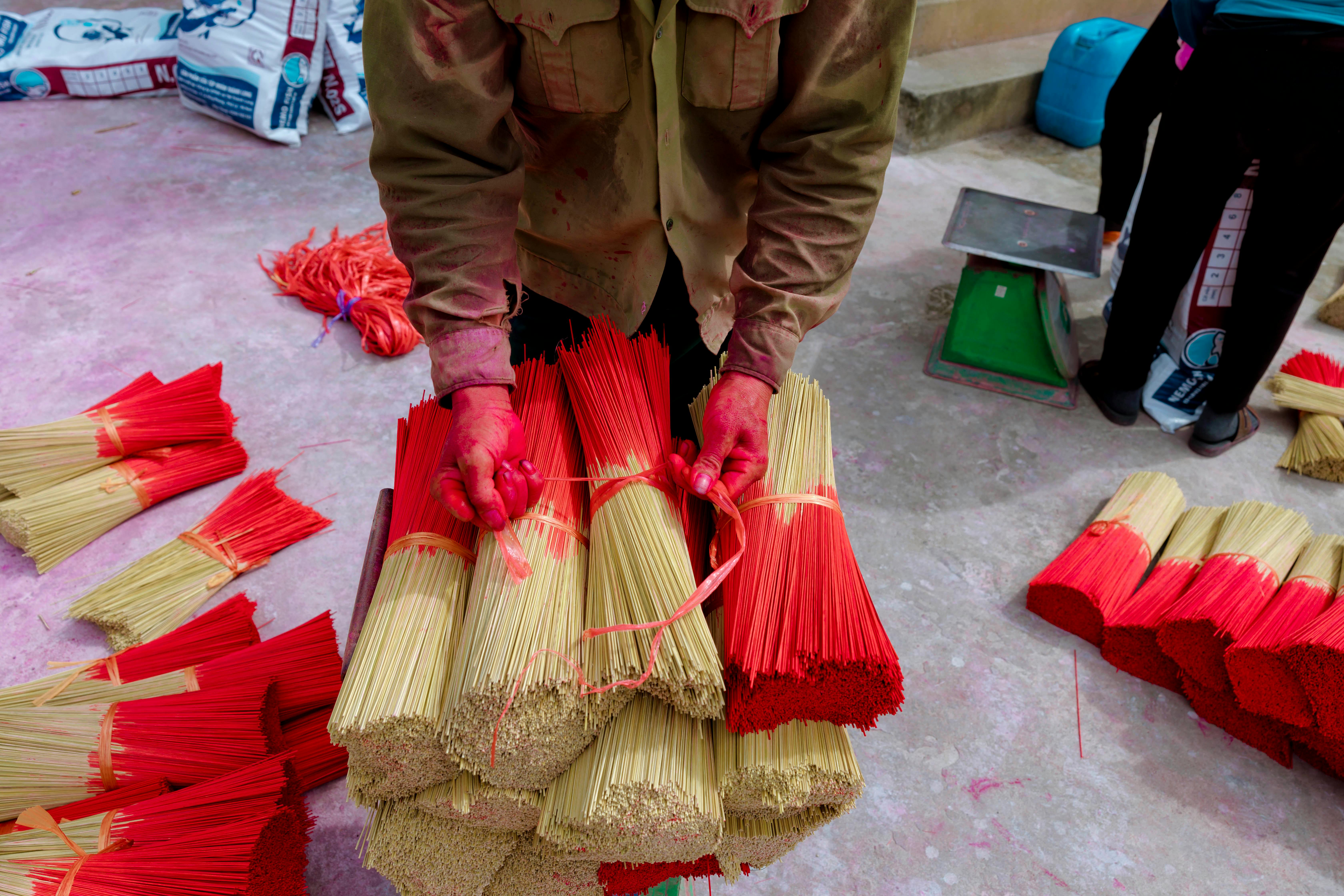 A man is holding a bundle of red sticks · Free Stock Photo