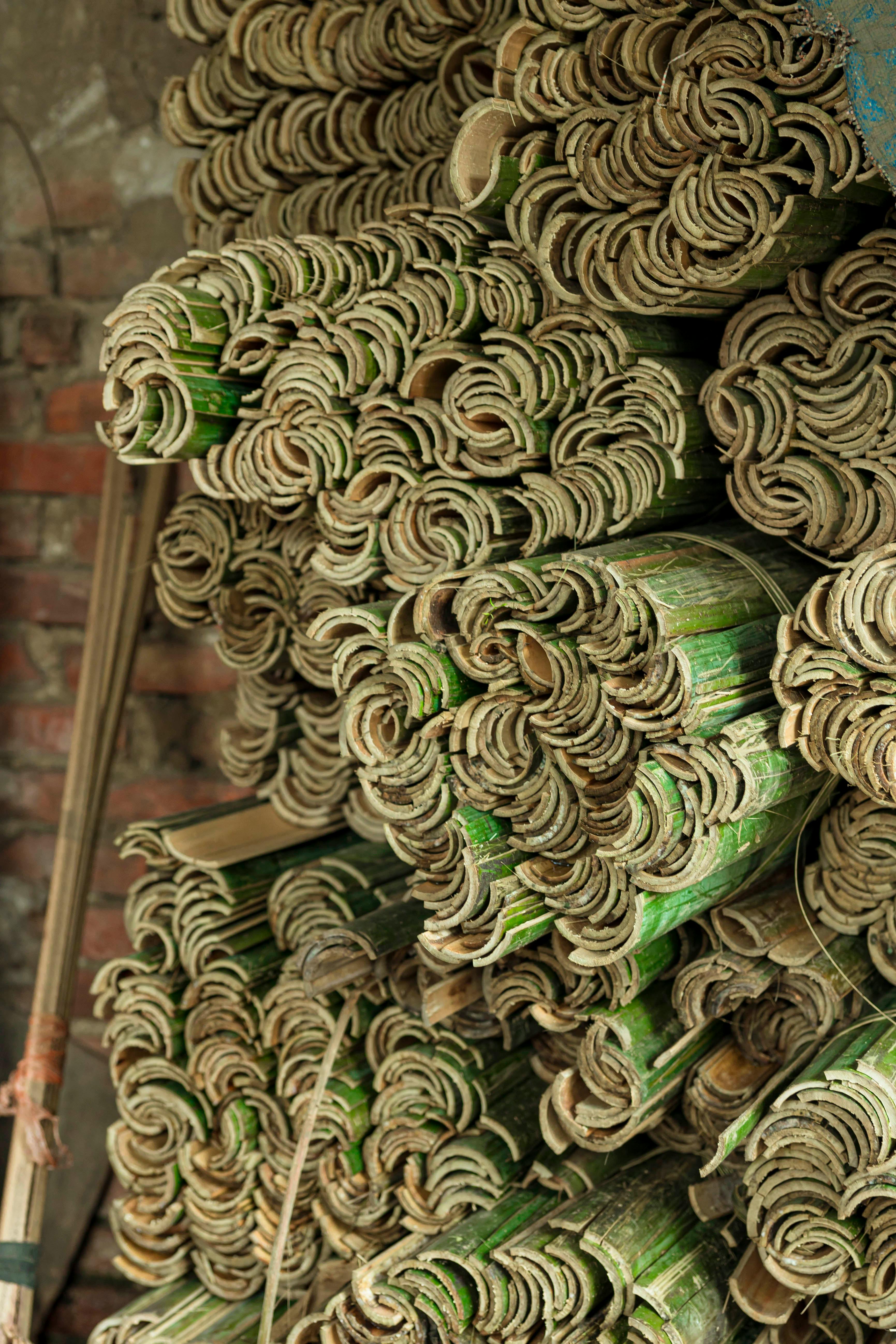 A pile of bamboo sticks stacked up against a wall · Free Stock Photo