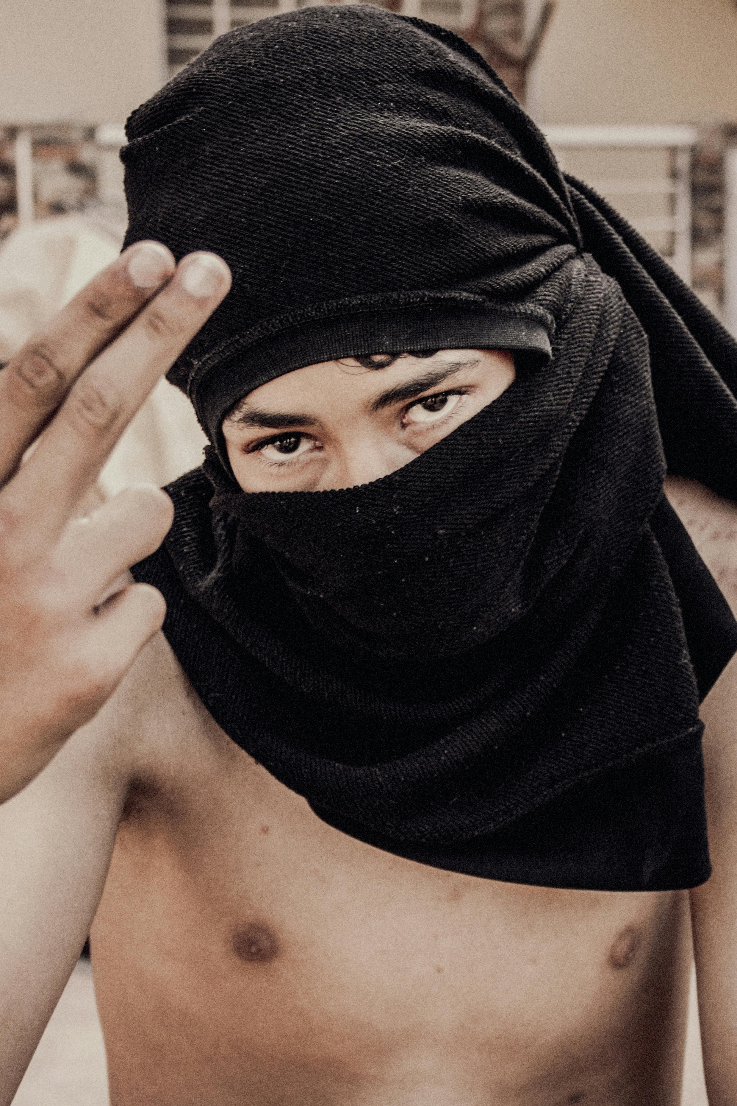 A man in a black head covering is making a peace sign · Free Stock Photo