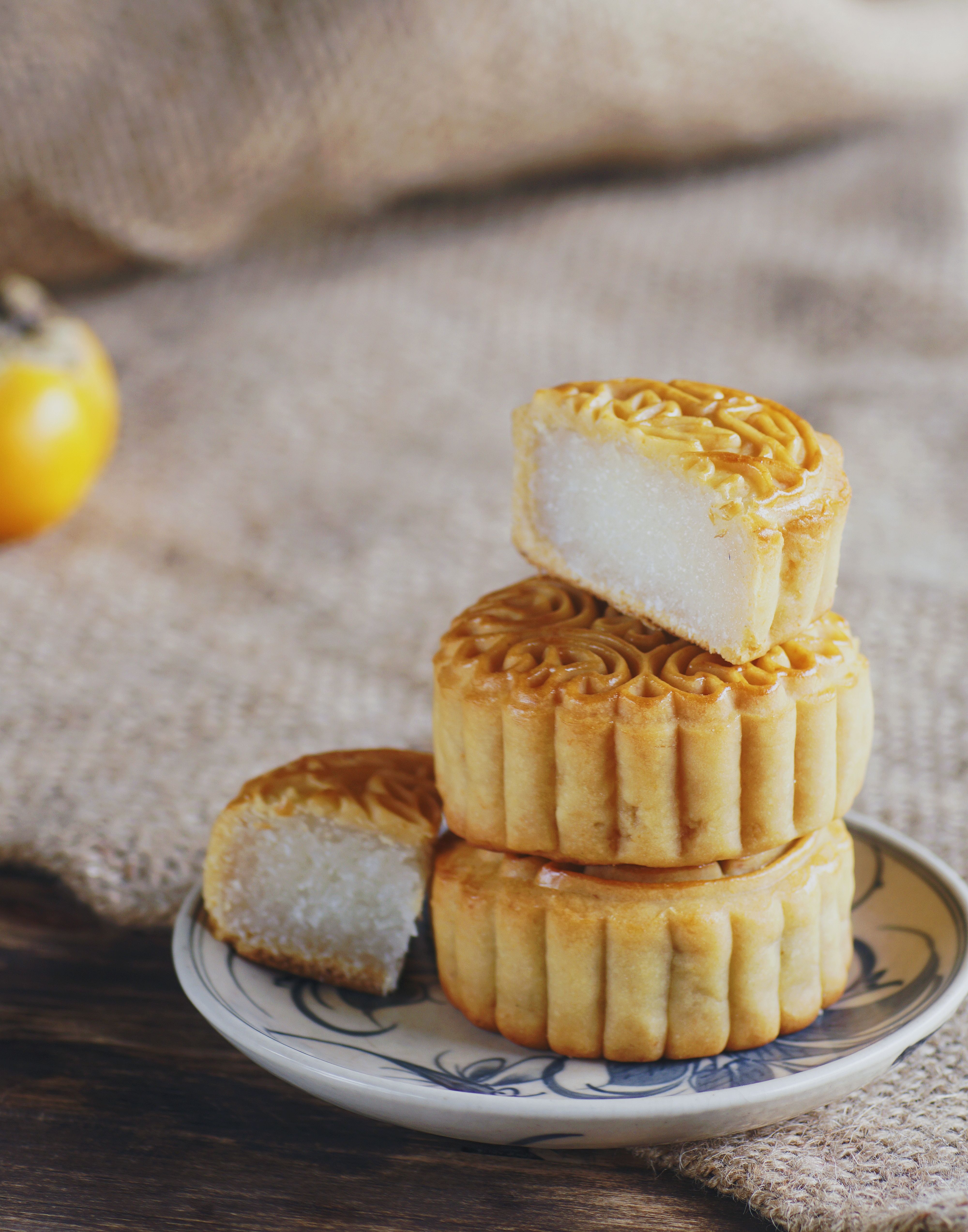 A stack of mooncakes on a plate with a small orange · Free Stock Photo