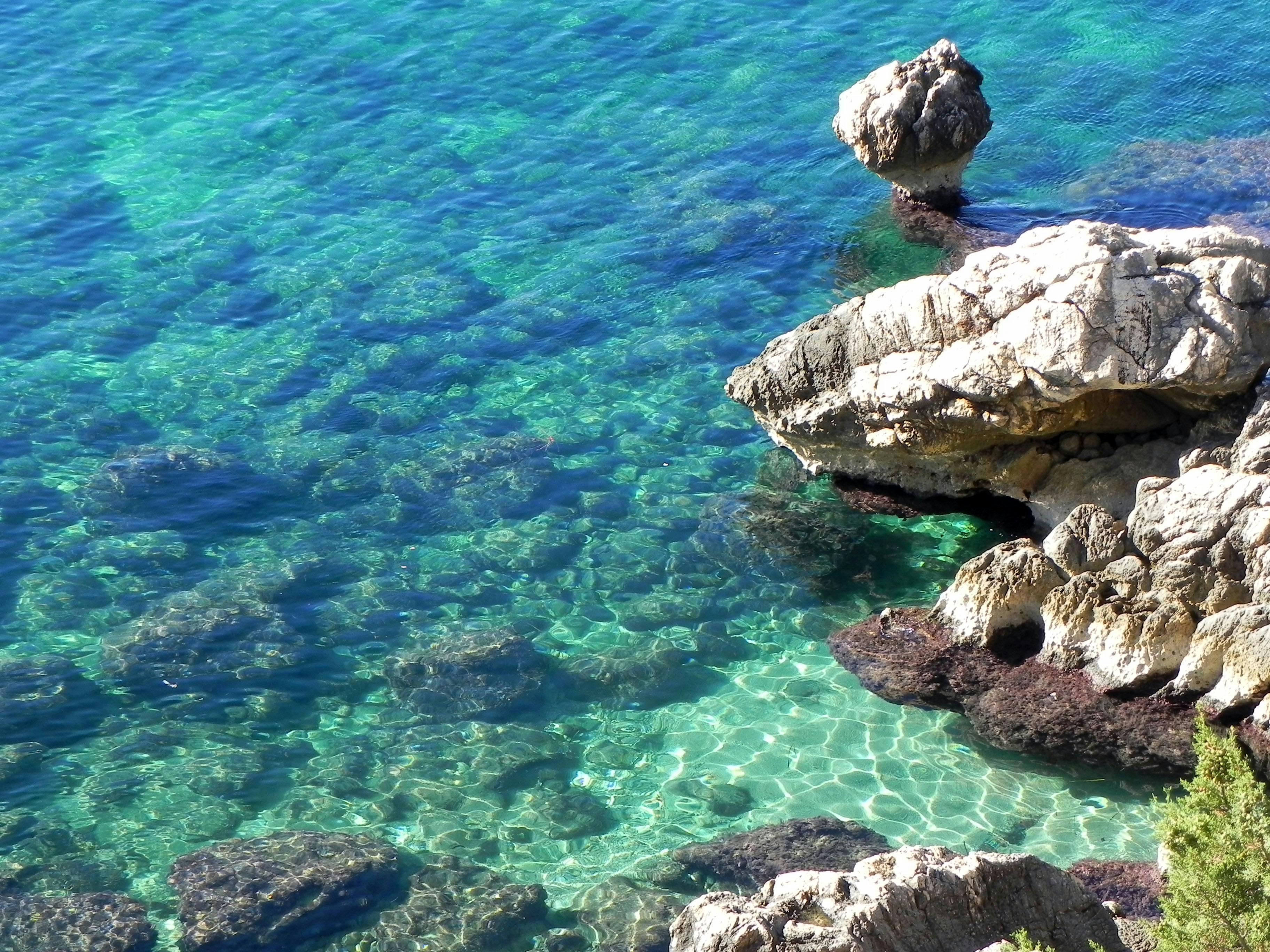A clear blue ocean with rocks and water · Free Stock Photo