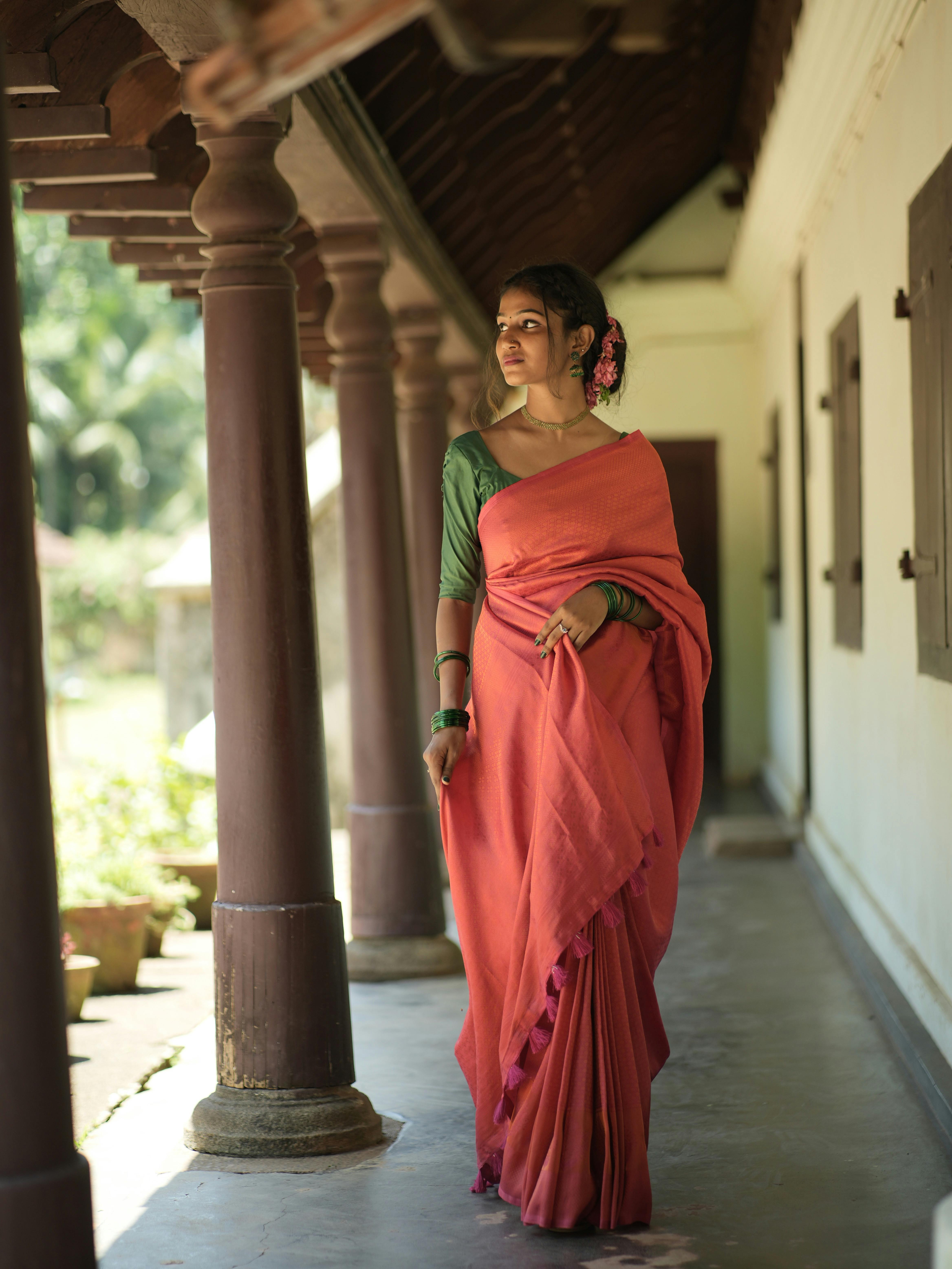 A woman in a pink sari walking down a corridor · Free Stock Photo