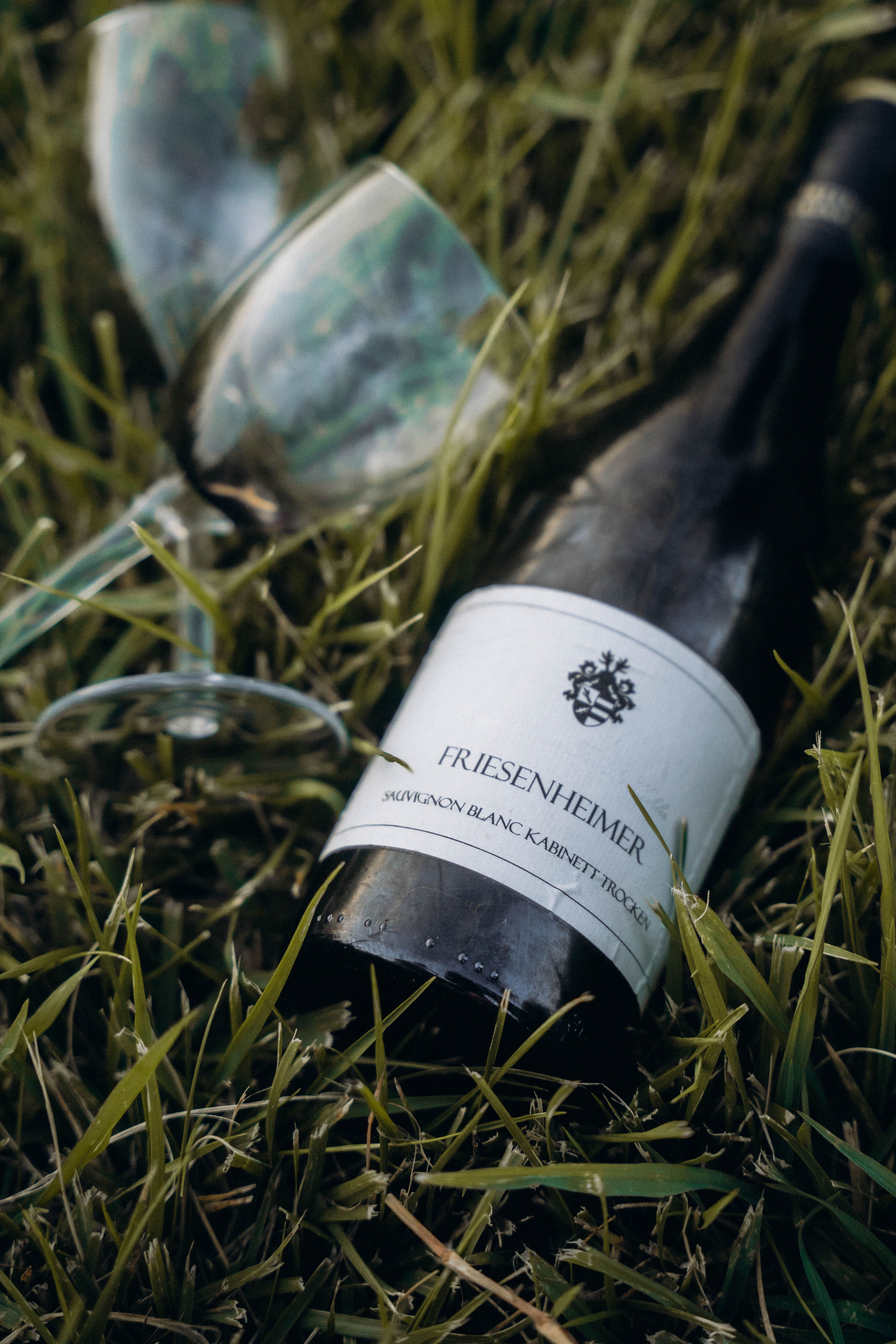 A bottle of wine and a glass sitting in the grass · Free Stock Photo