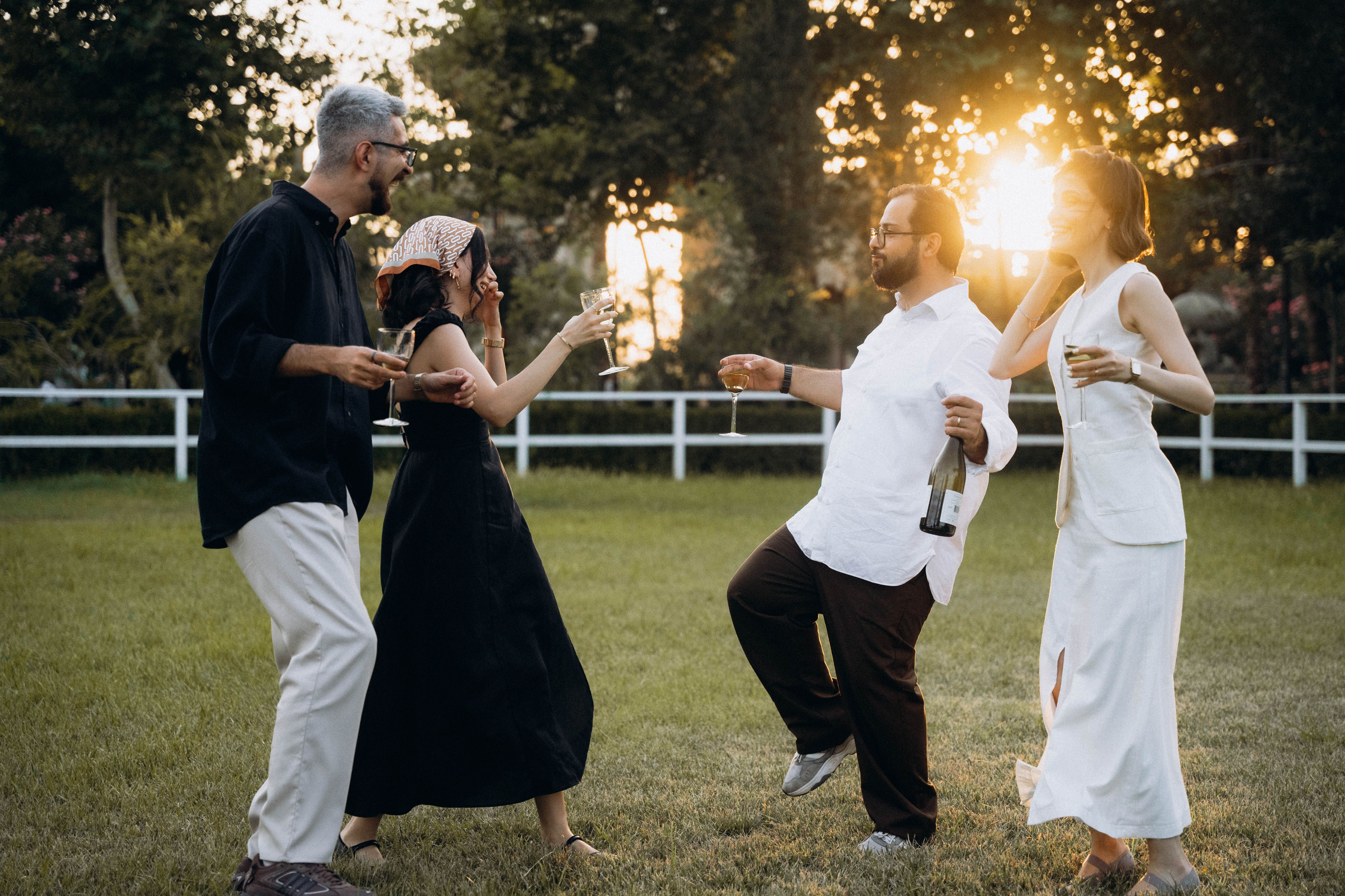 A group of people dancing in a field at sunset · Free Stock Photo