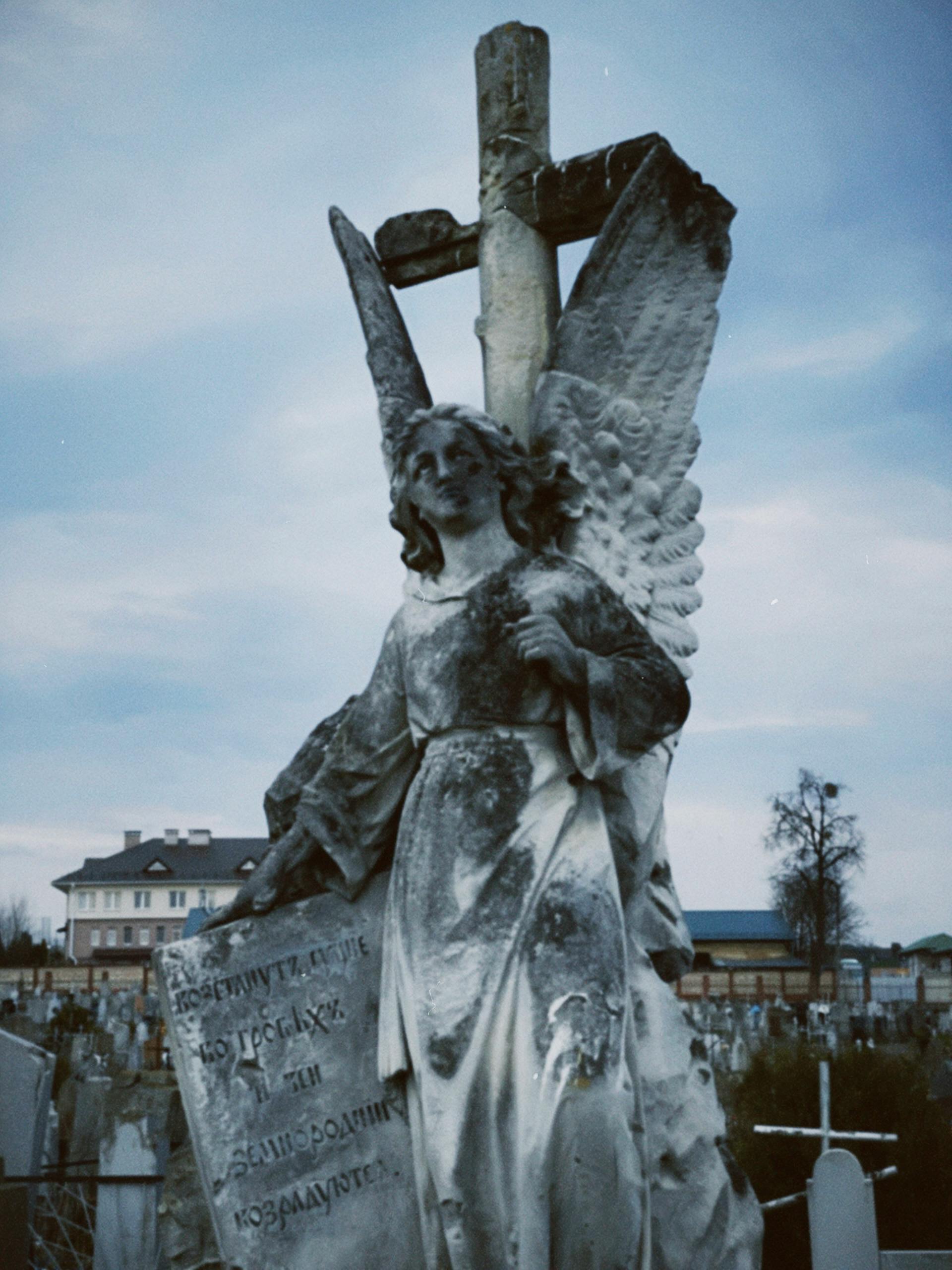 An angel statue with a cross on top of it · Free Stock Photo