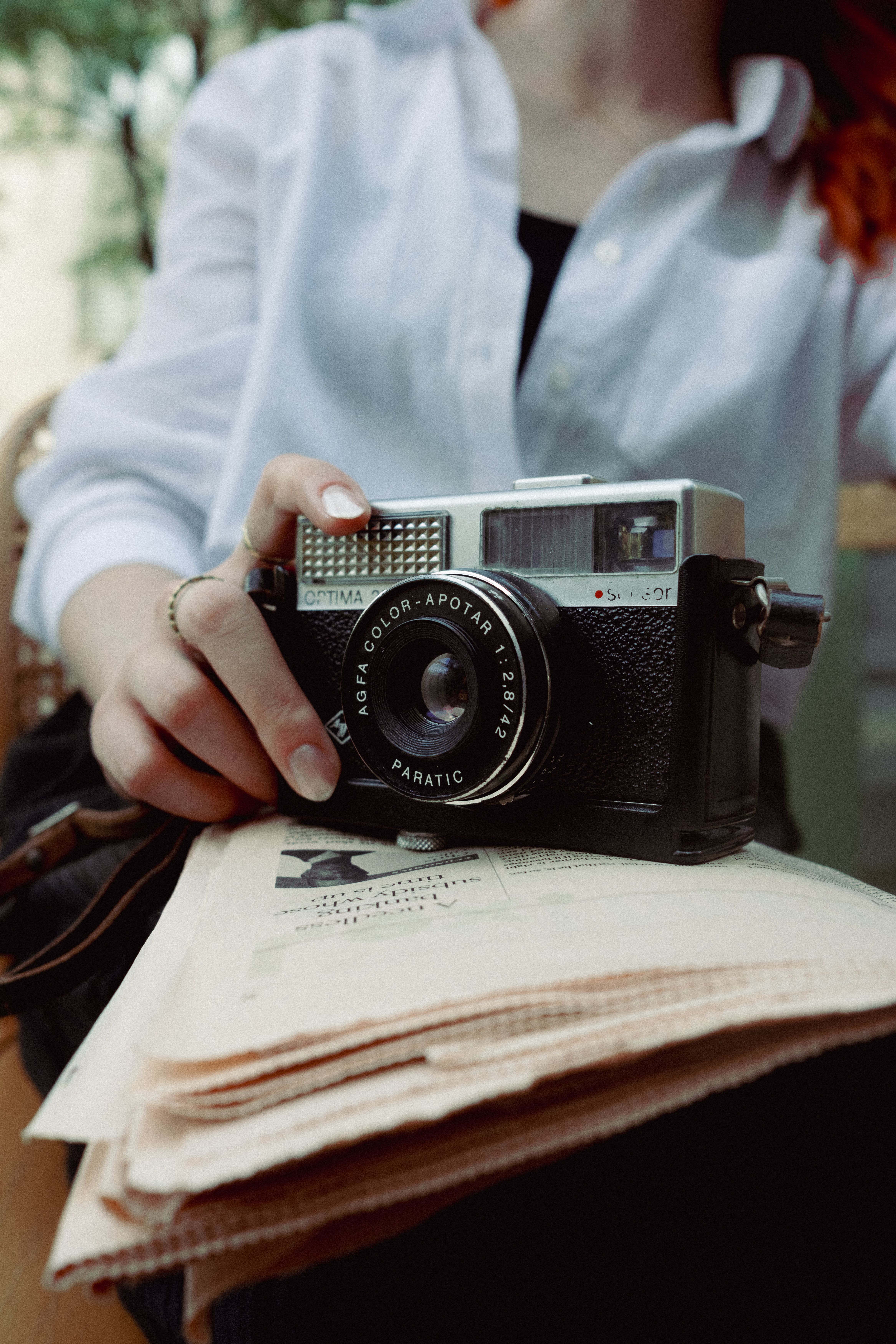 A woman holding a camera and reading a newspaper · Free Stock Photo
