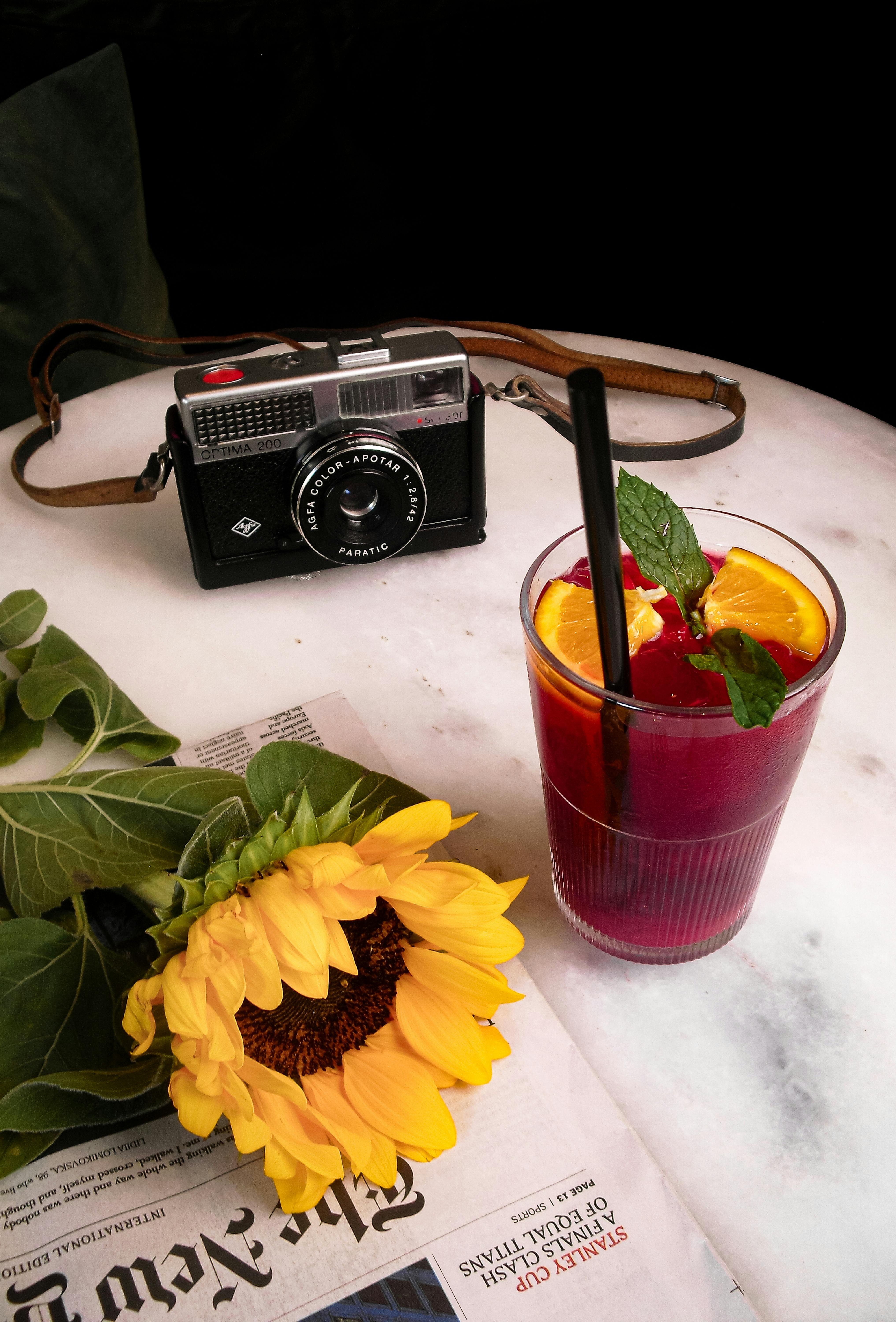 Table with Camera, Drink and Sunflower · Free Stock Photo