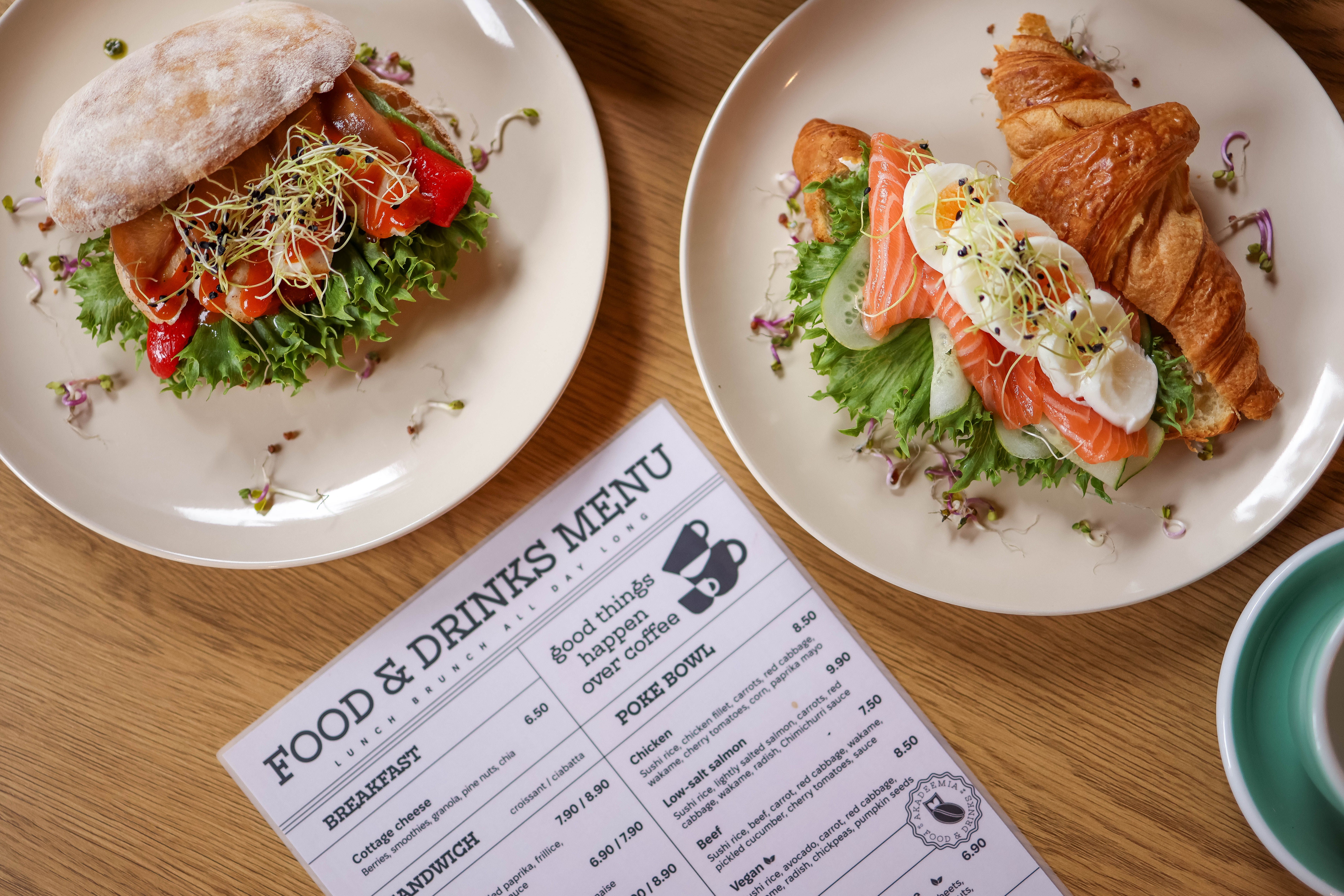 Two sandwiches on plates with a menu and a cup of coffee · Free Stock Photo