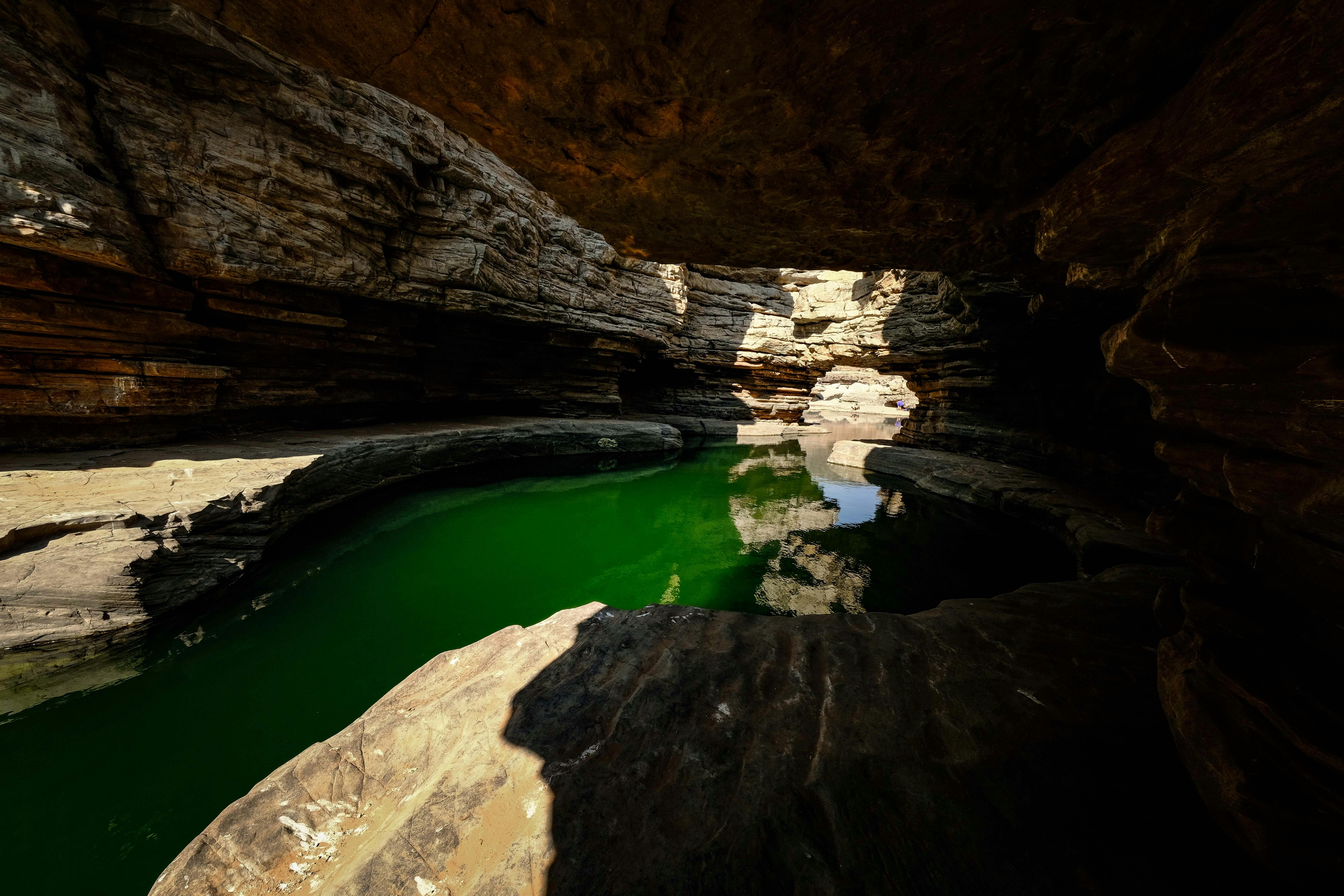 A green pool in a cave with rocks · Free Stock Photo